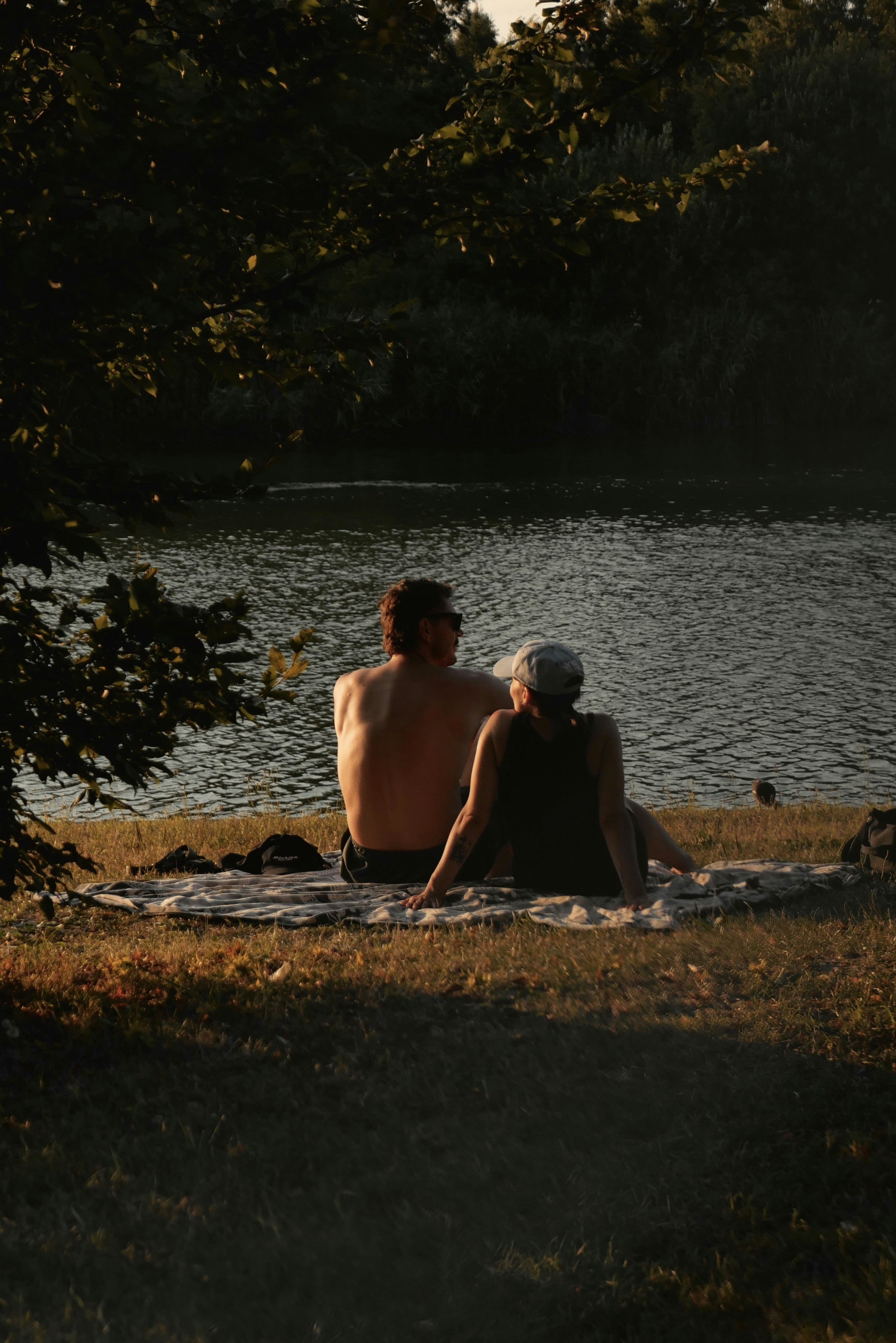 Evening by the Lake: Two Silhouettes on a Sunlit Blanket