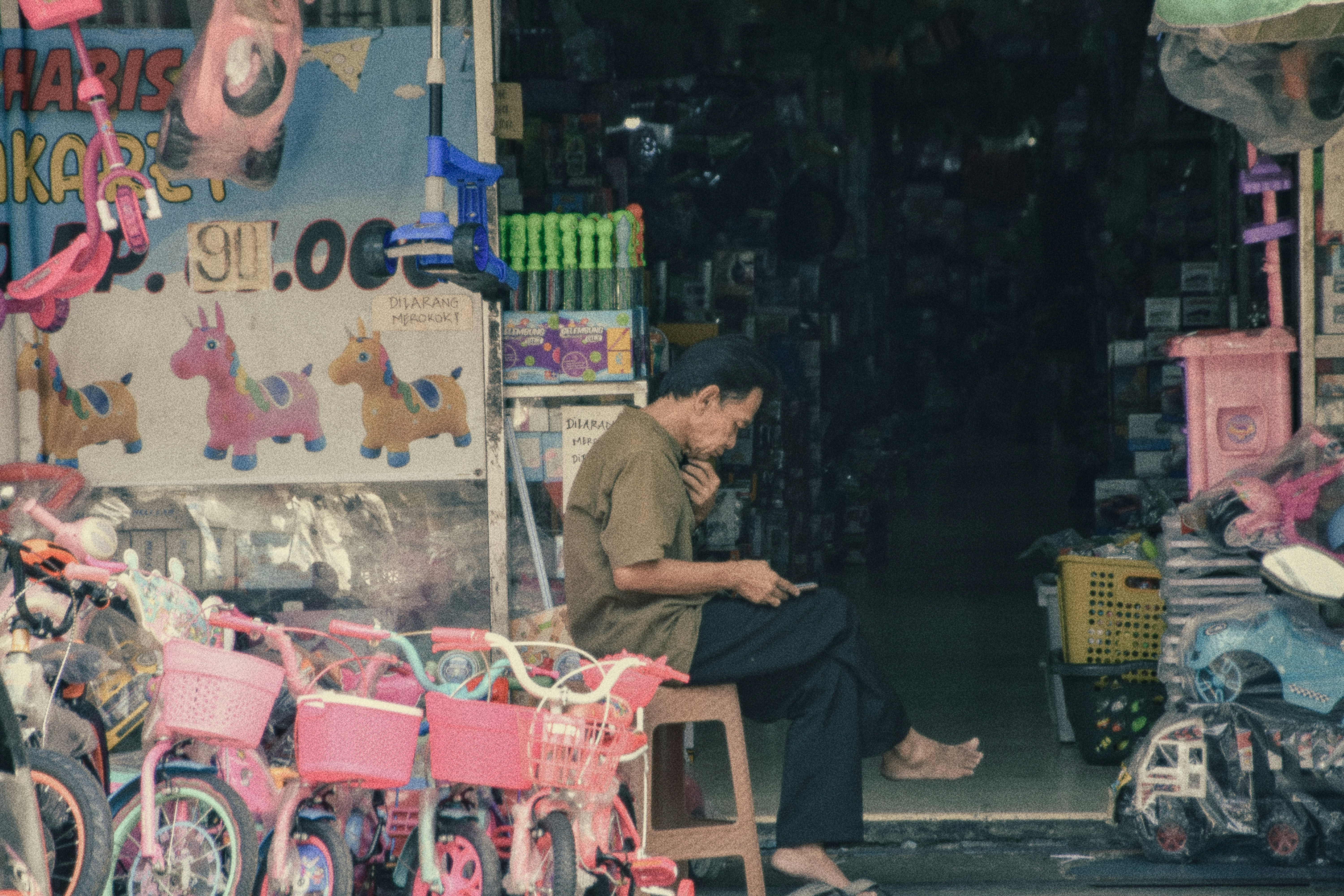 The Quiet Shopkeeper: A Moment of Solitude Amid a Colorful Street Bazaar