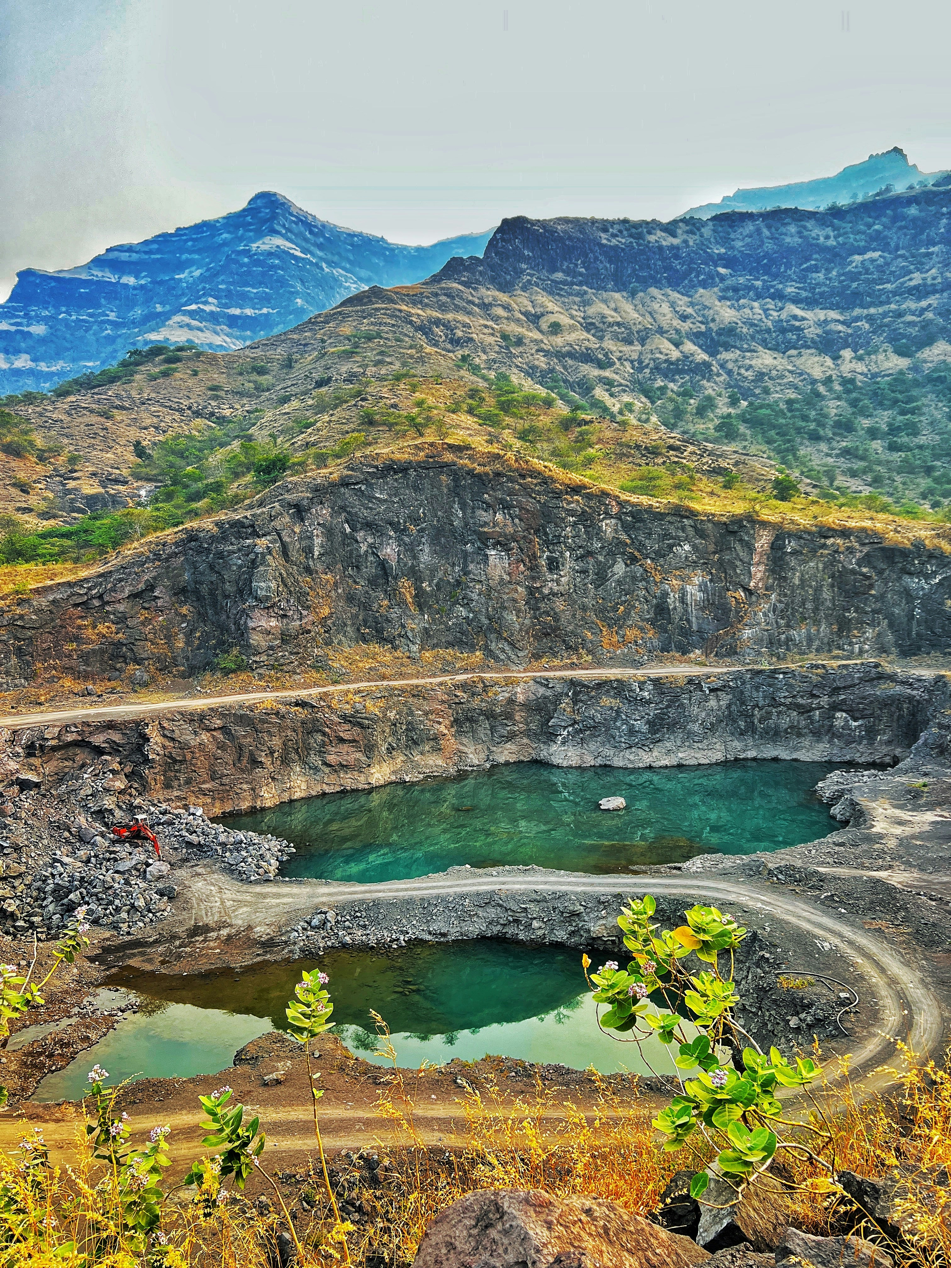 Verdant Rim of a Quarry Crater Nestled Between Rugged Peaks