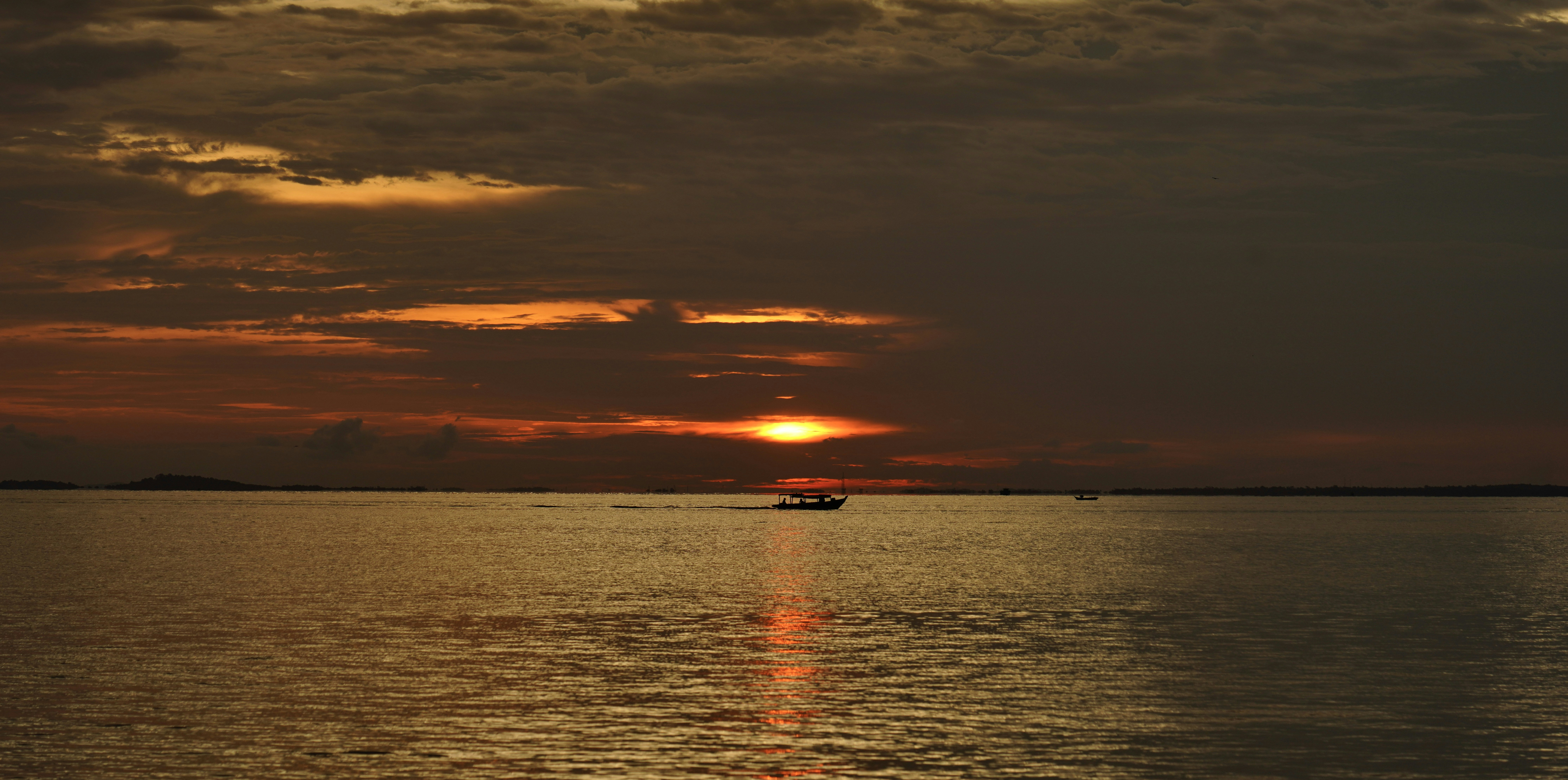 Fiery Horizon: A Solitary Boat at Sunset