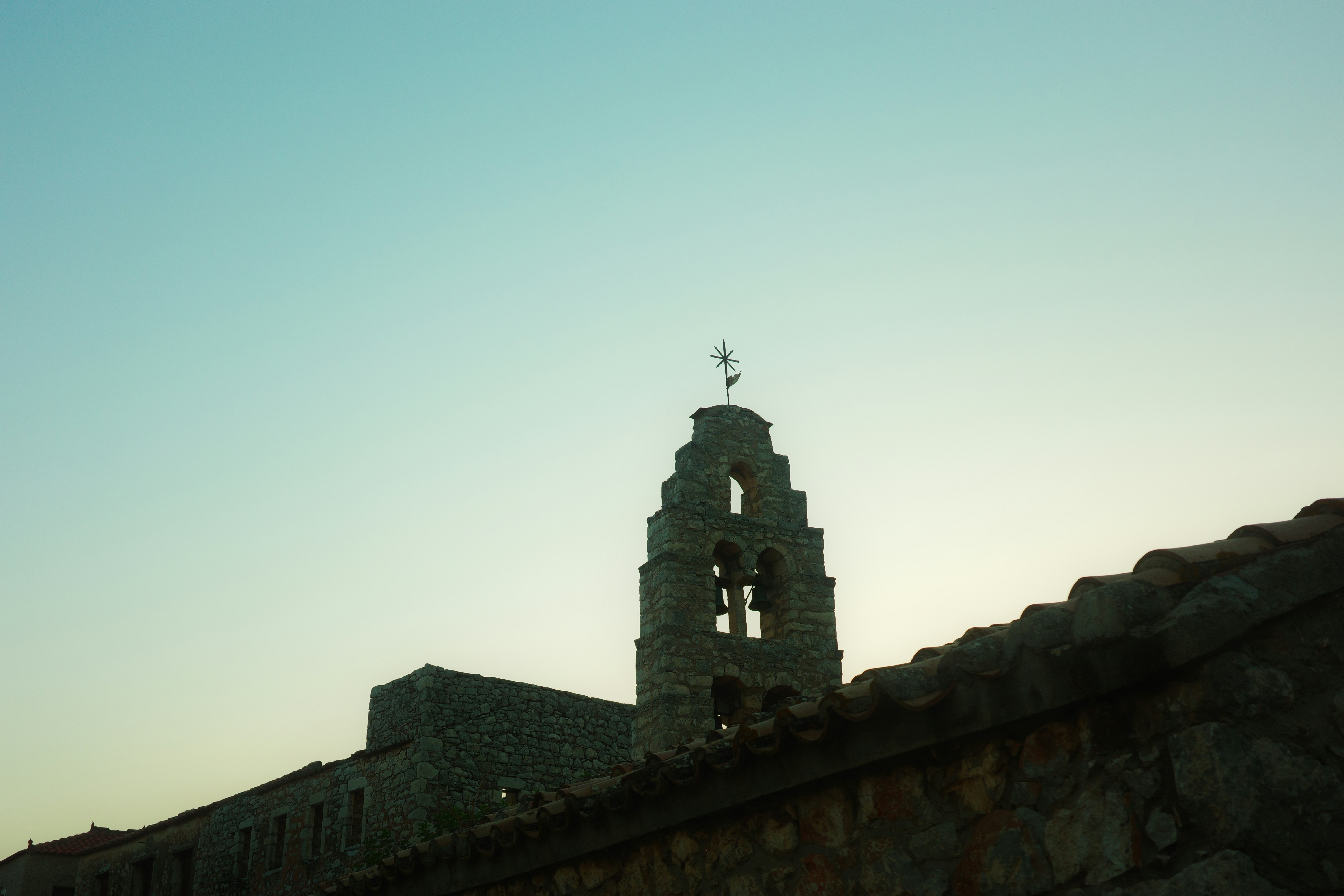 Sunlit Bell Tower Crest over Aged Stone Wall