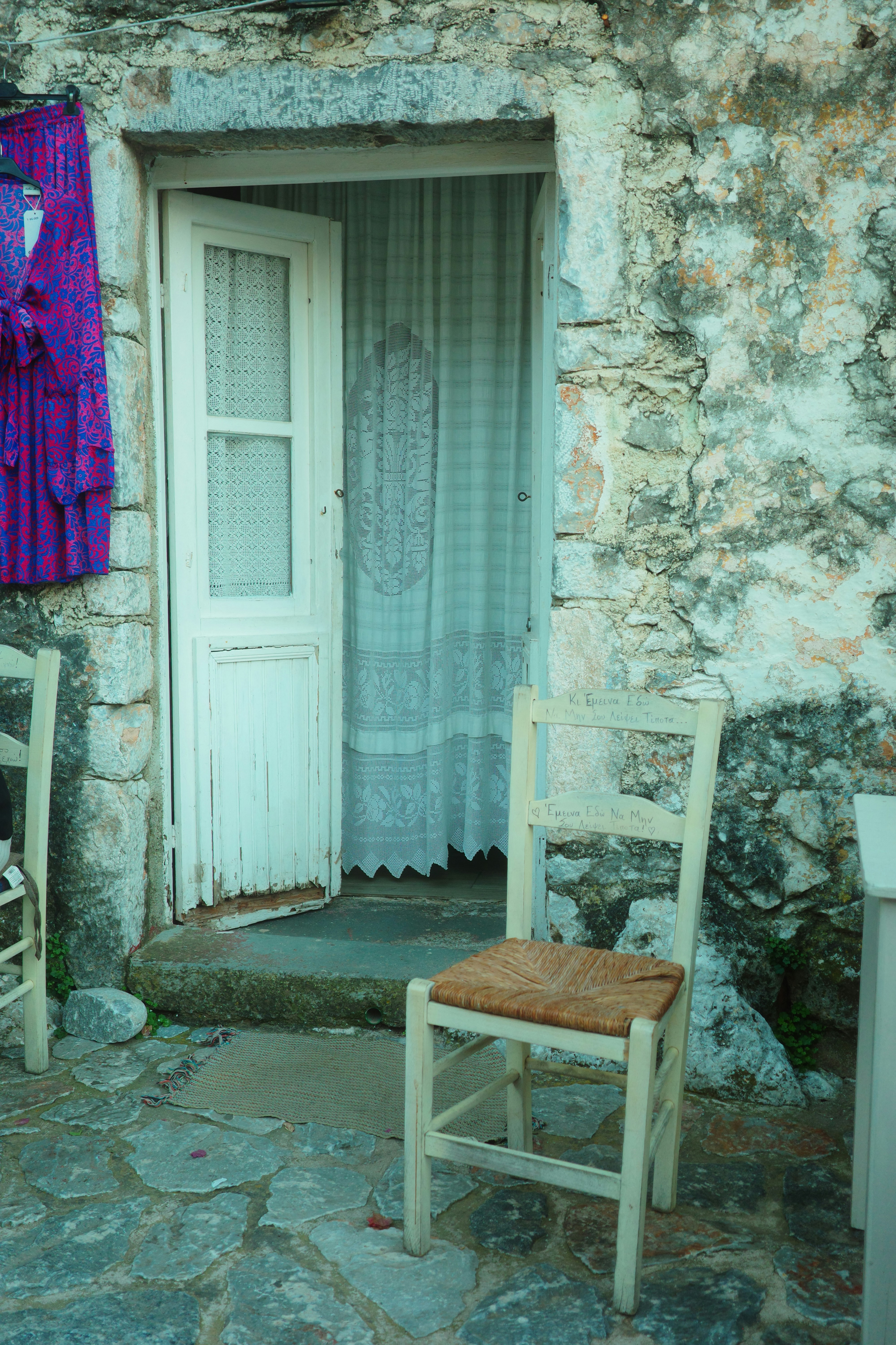 Weathered doorway with patinaed chairs in a sunlit stone alcove