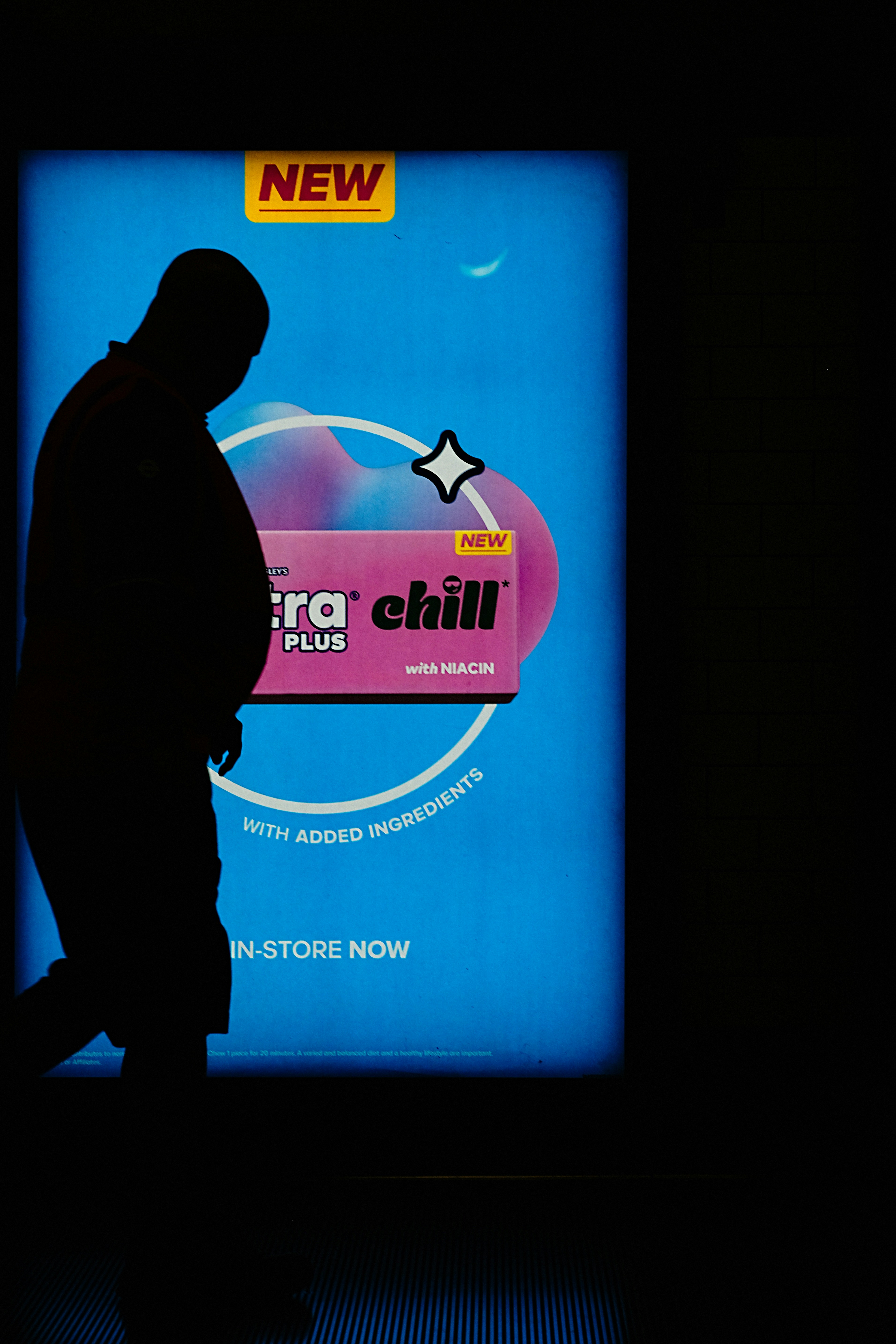 Silhouette in Front of Neon Blue Ad Panel