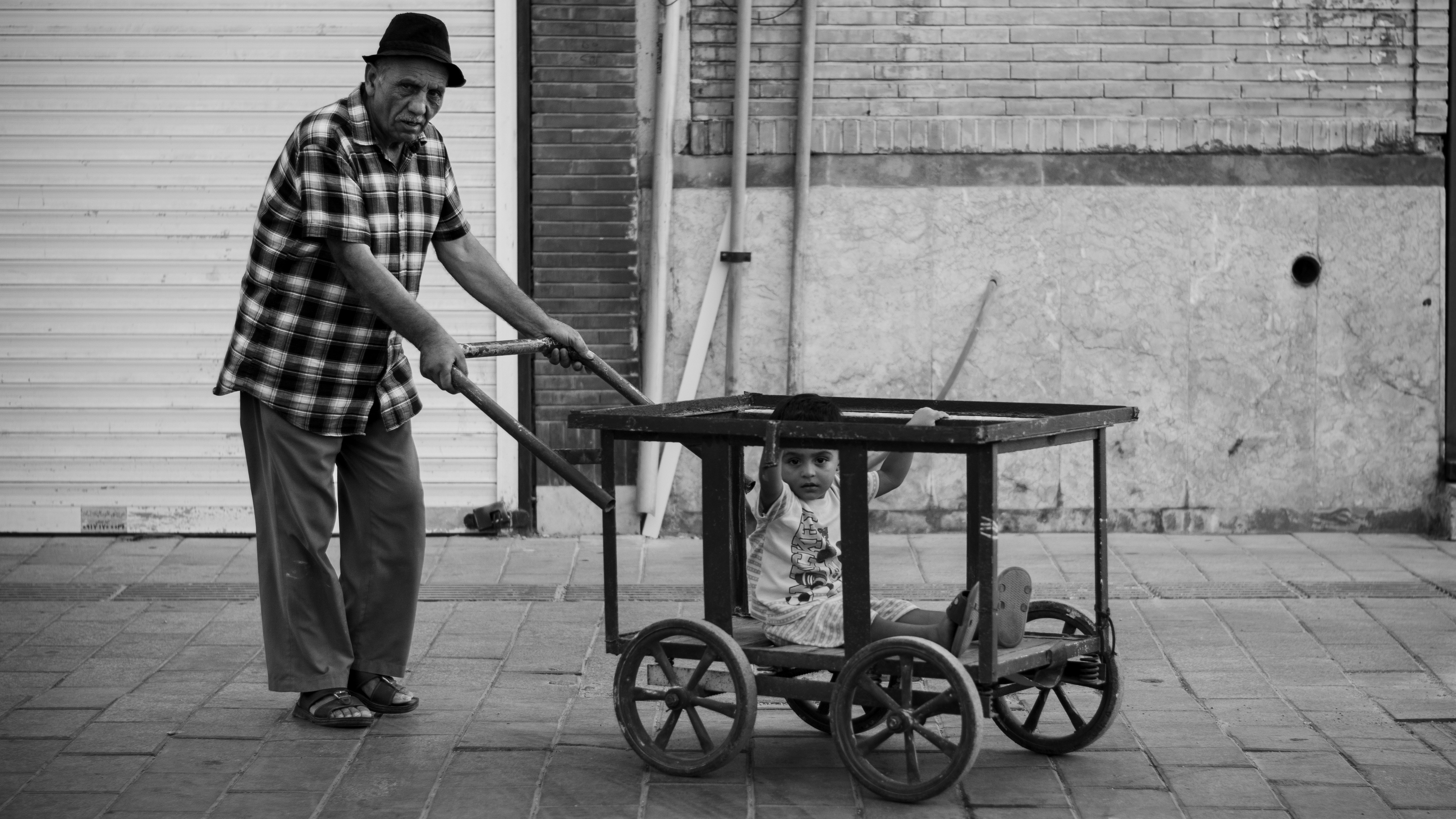 Grounded Moments: A Grandfather Pushes a Carriage Carrying a Child