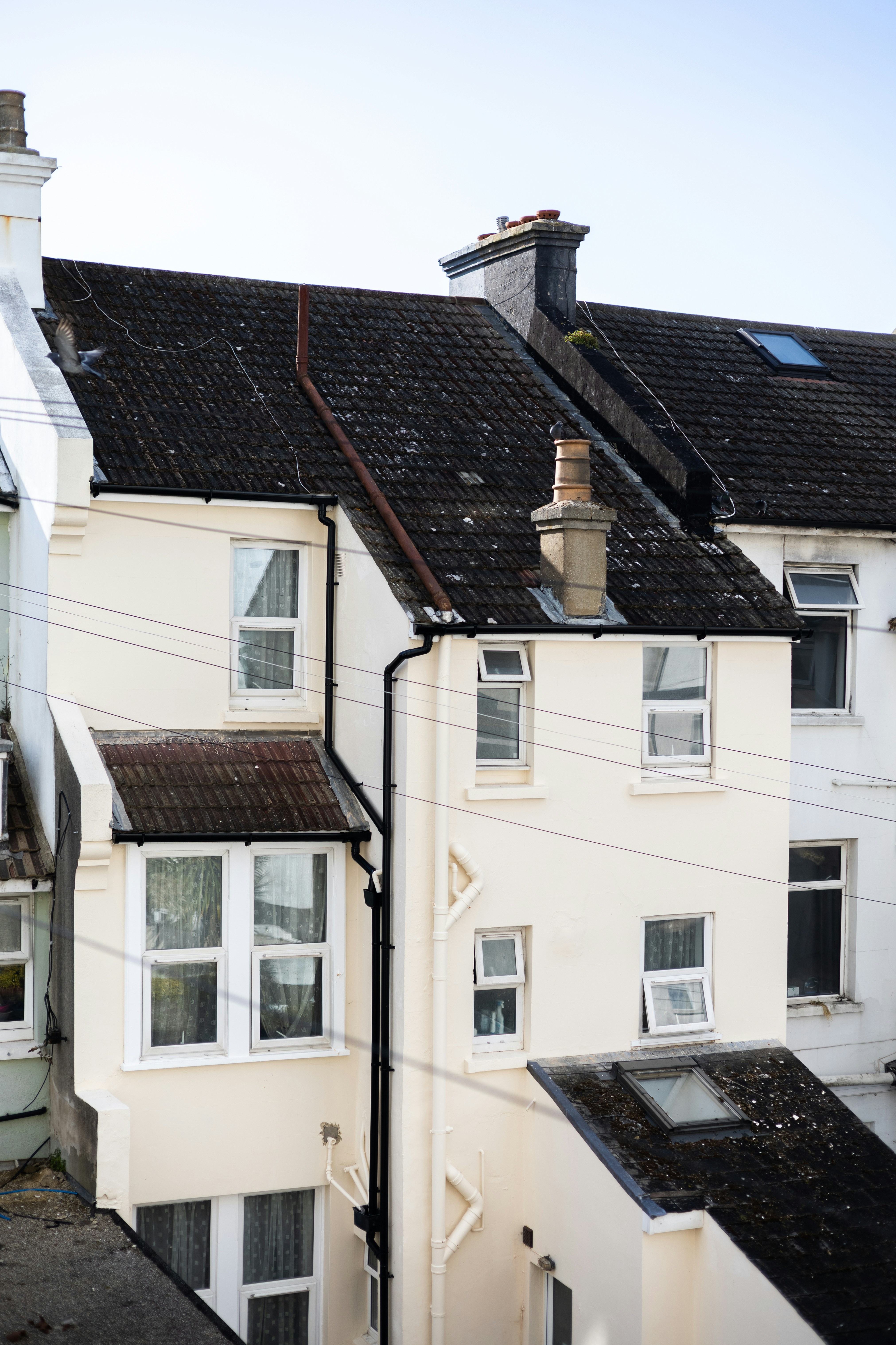 Row of sunlit terraced homes with sloped roofs and chimney stacks
