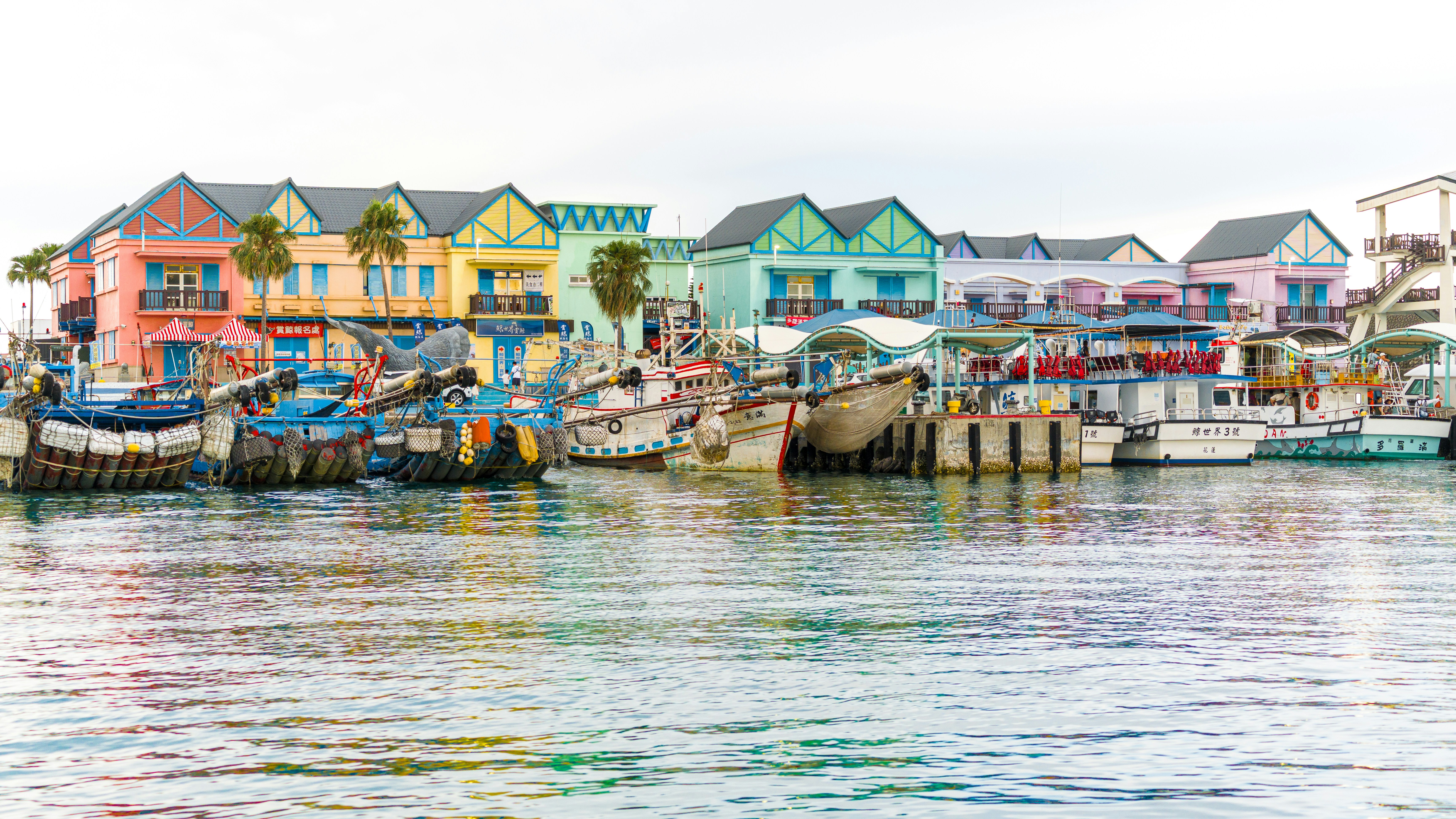 Colorful Waterfront Row: Boats and Beach Houses Reflecting a Quiet Harbor