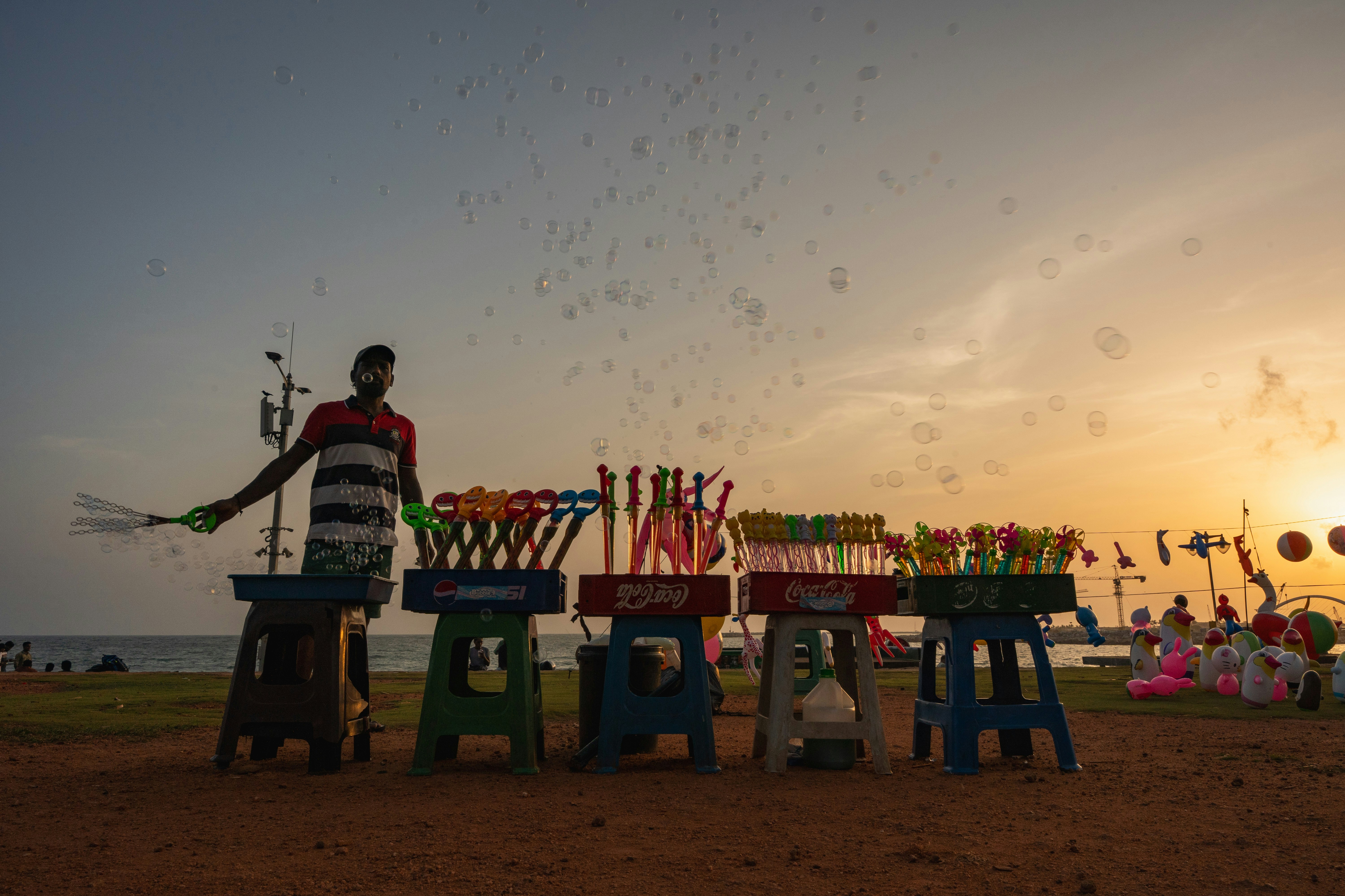 Stall of Color: Toy Skewers and Balloons at Dusk by the Ocean