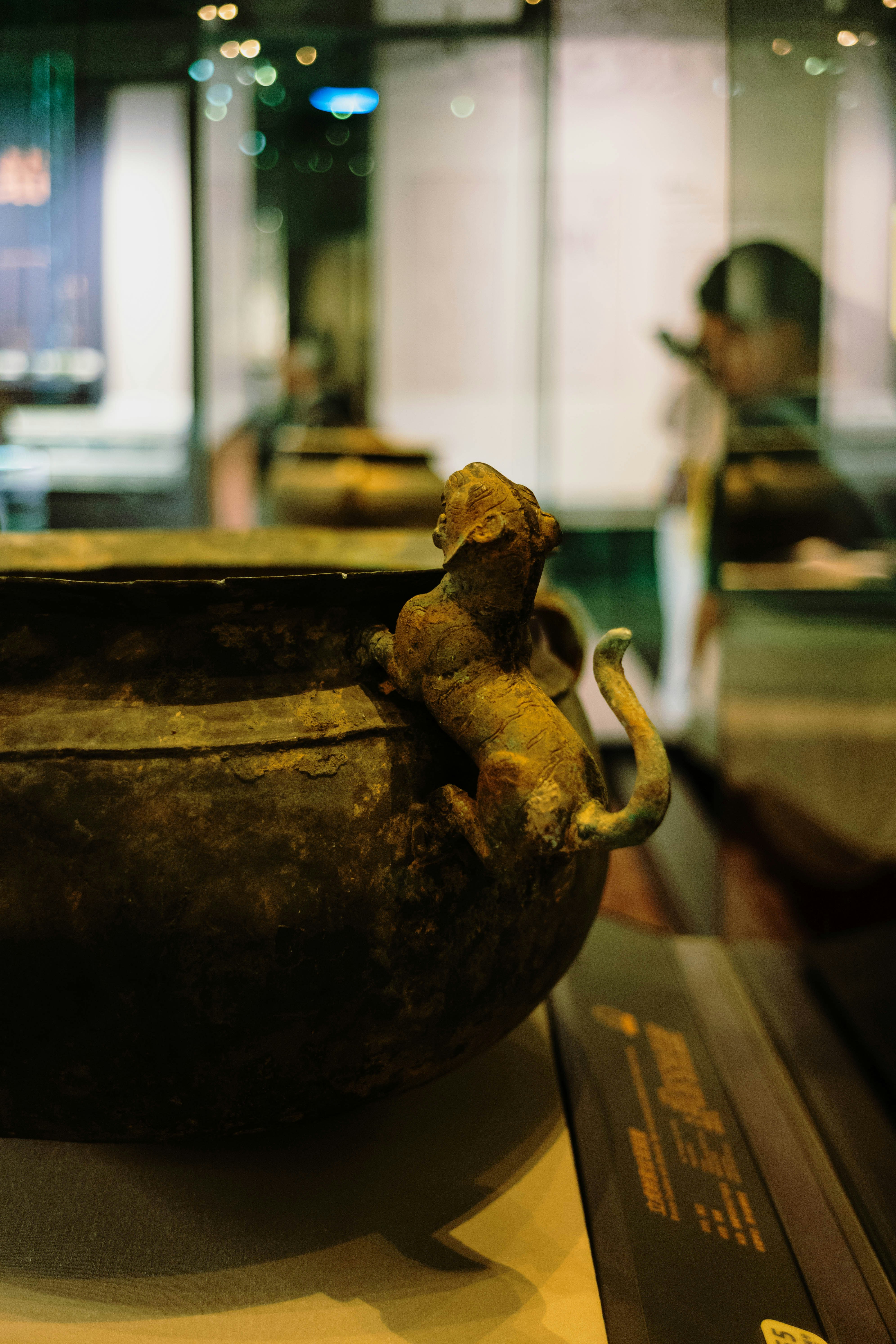 Old Vessel, Silent Guard: A Bronze Figure Anchored on a Weathered Pot
