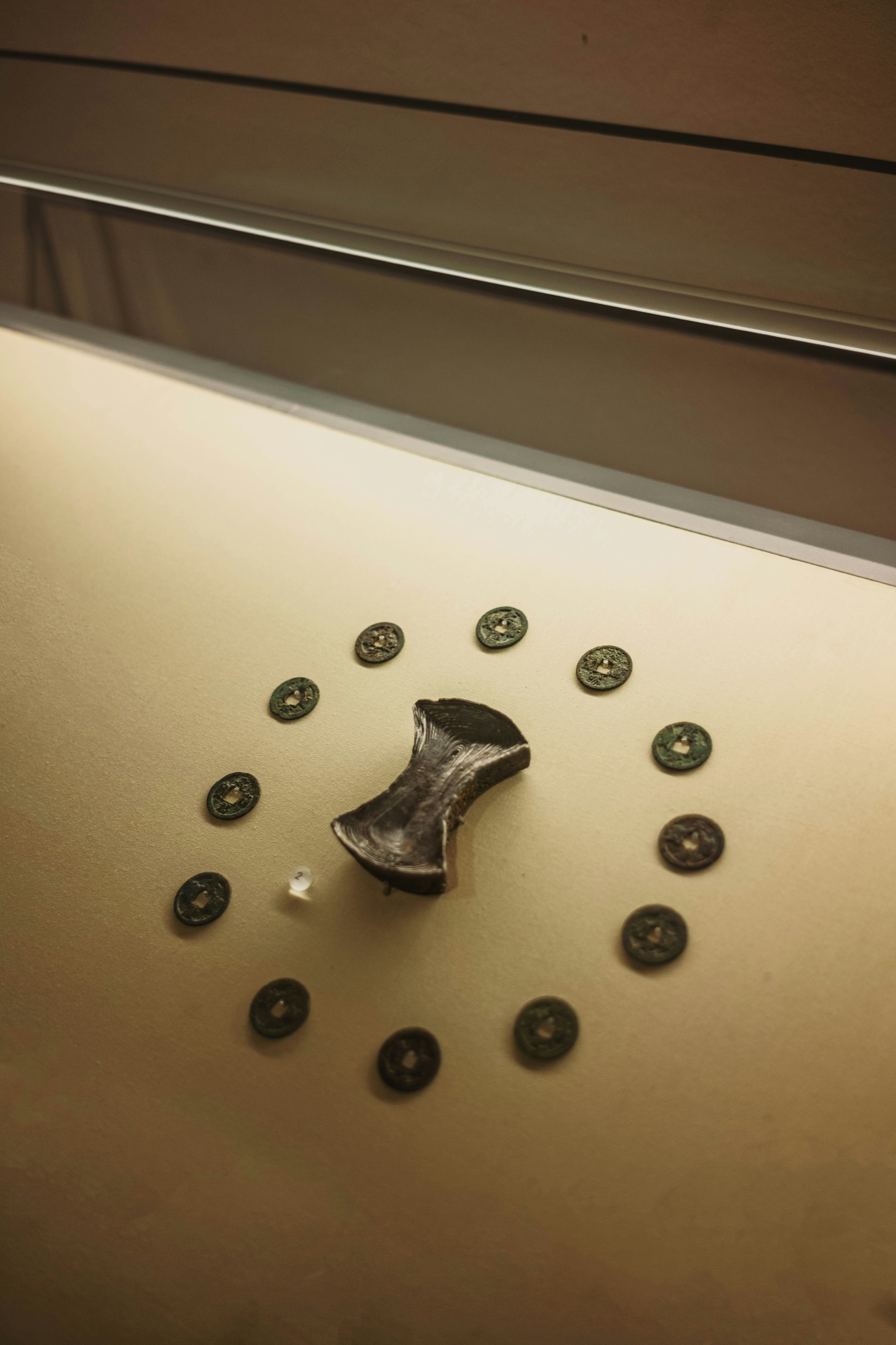 Arc of coins encircling a chipped fragment on a metallic surface