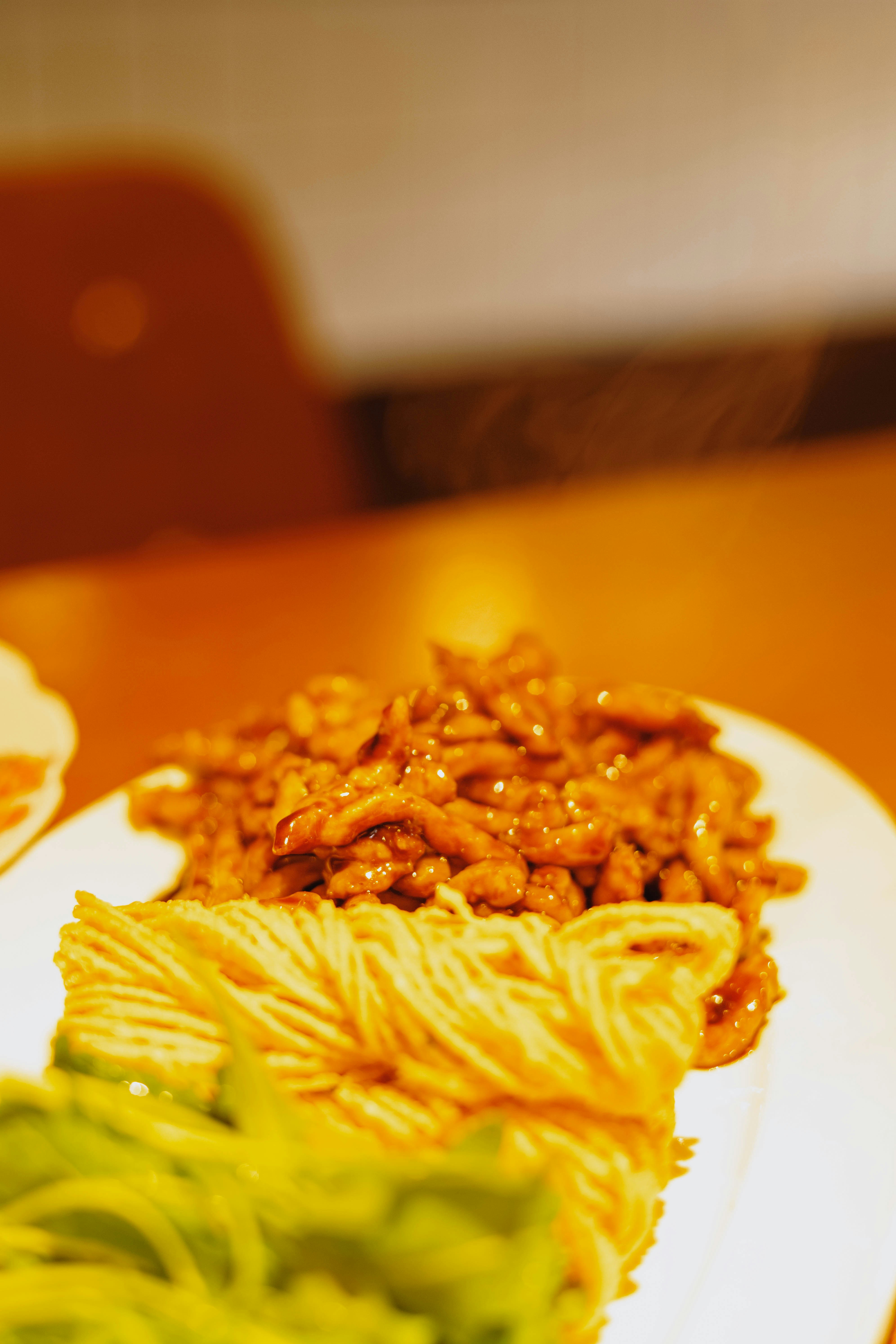 Golden Noodles and Glazed Meat Dominate a Warmly Lit Plate