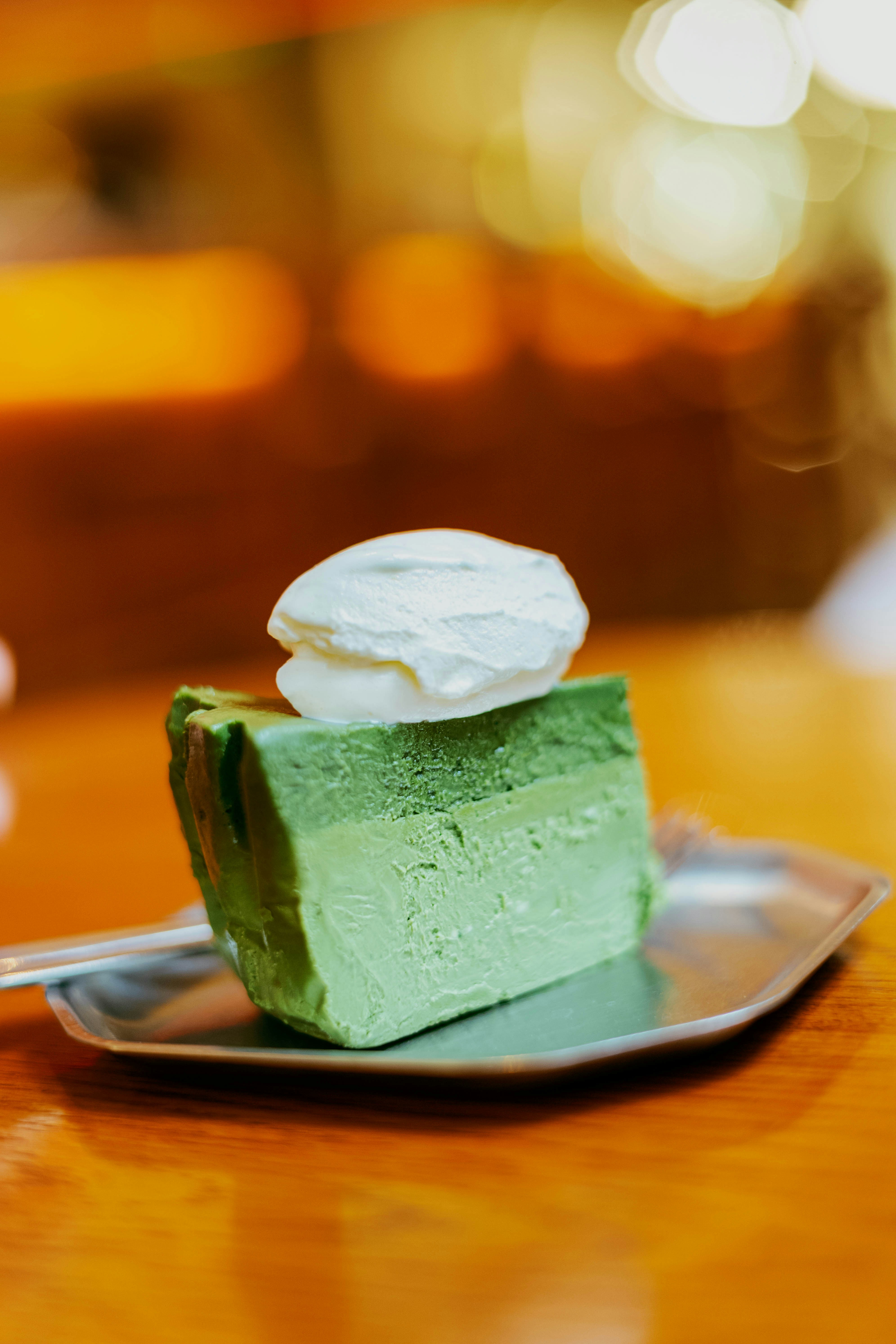 Green tea cake with cloud of cream on a reflective plate