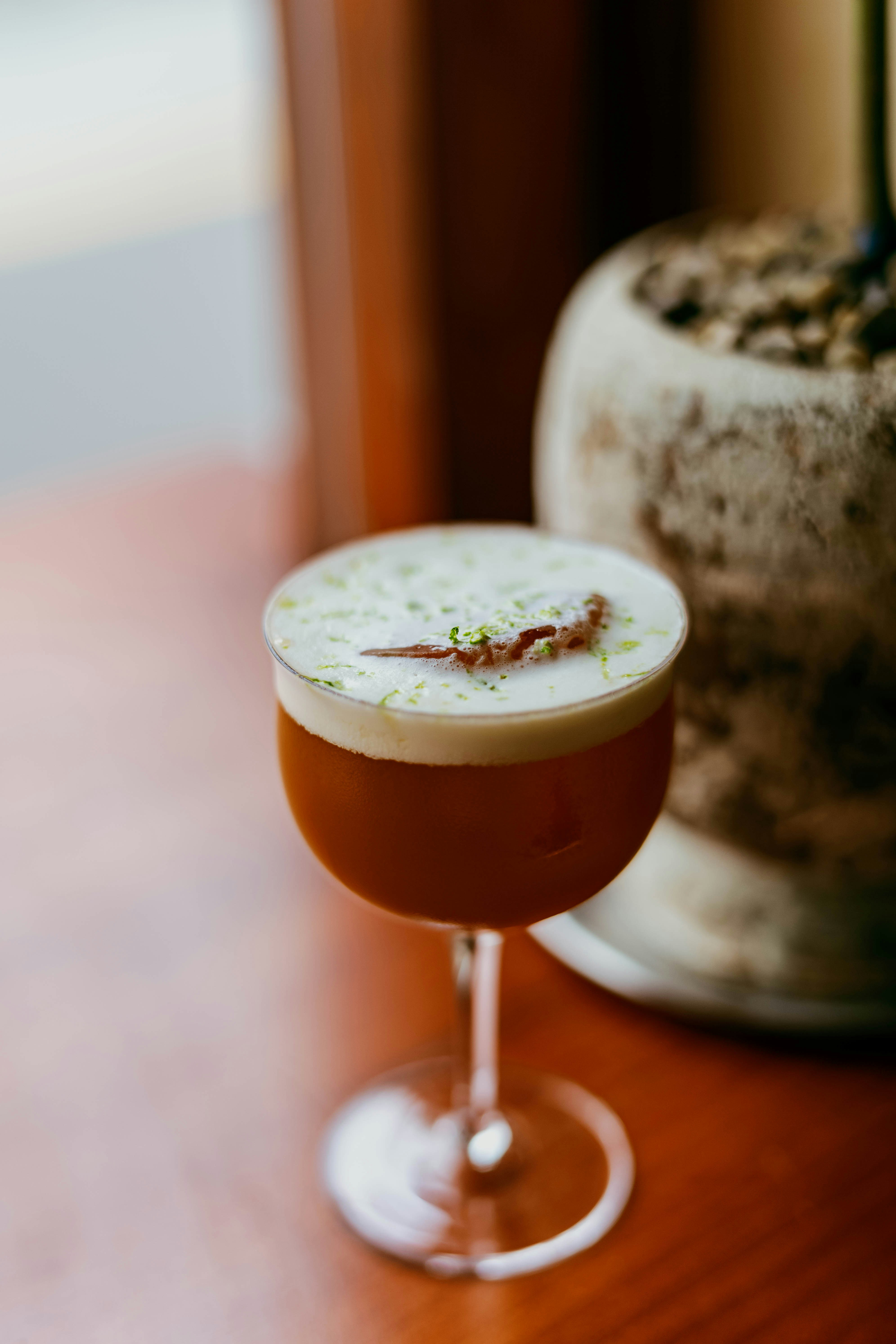 Stemmed Elegance: A Glass of Foamy Amber on a Wooden Counter