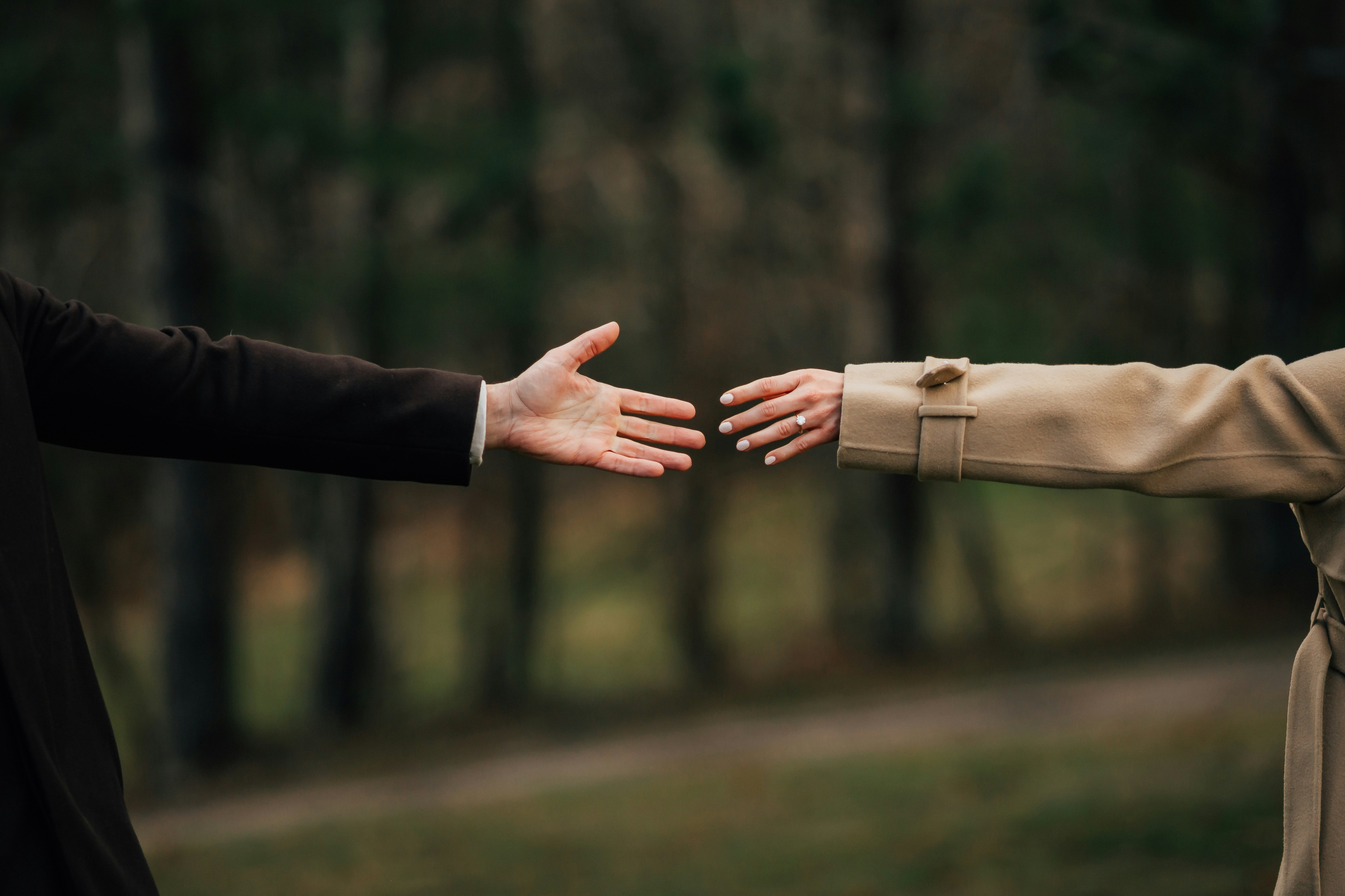 A Pause in Contact: Hands Reaching Across a Quiet Path