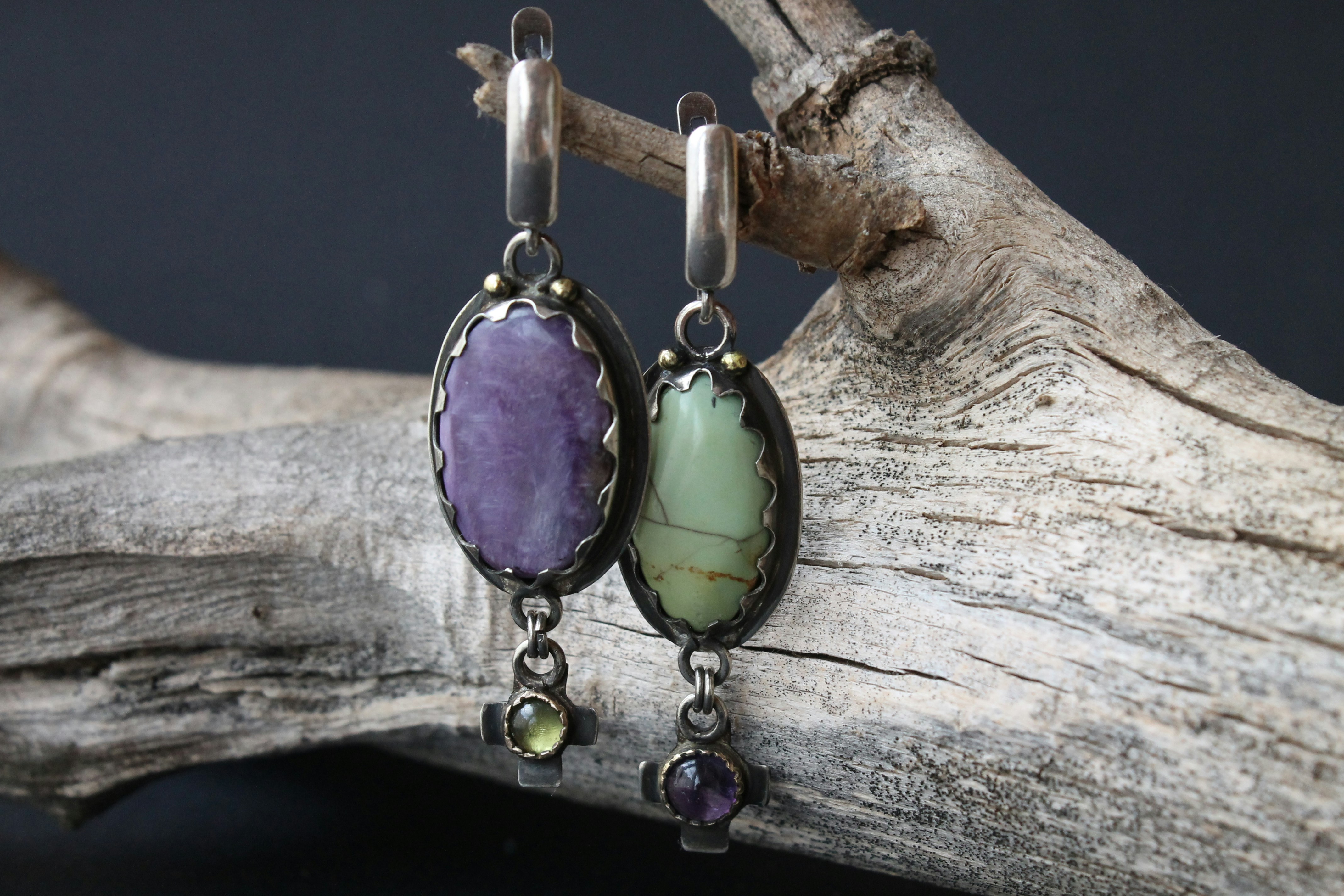 Purple and green gemstones on weathered driftwood with dangling pendants