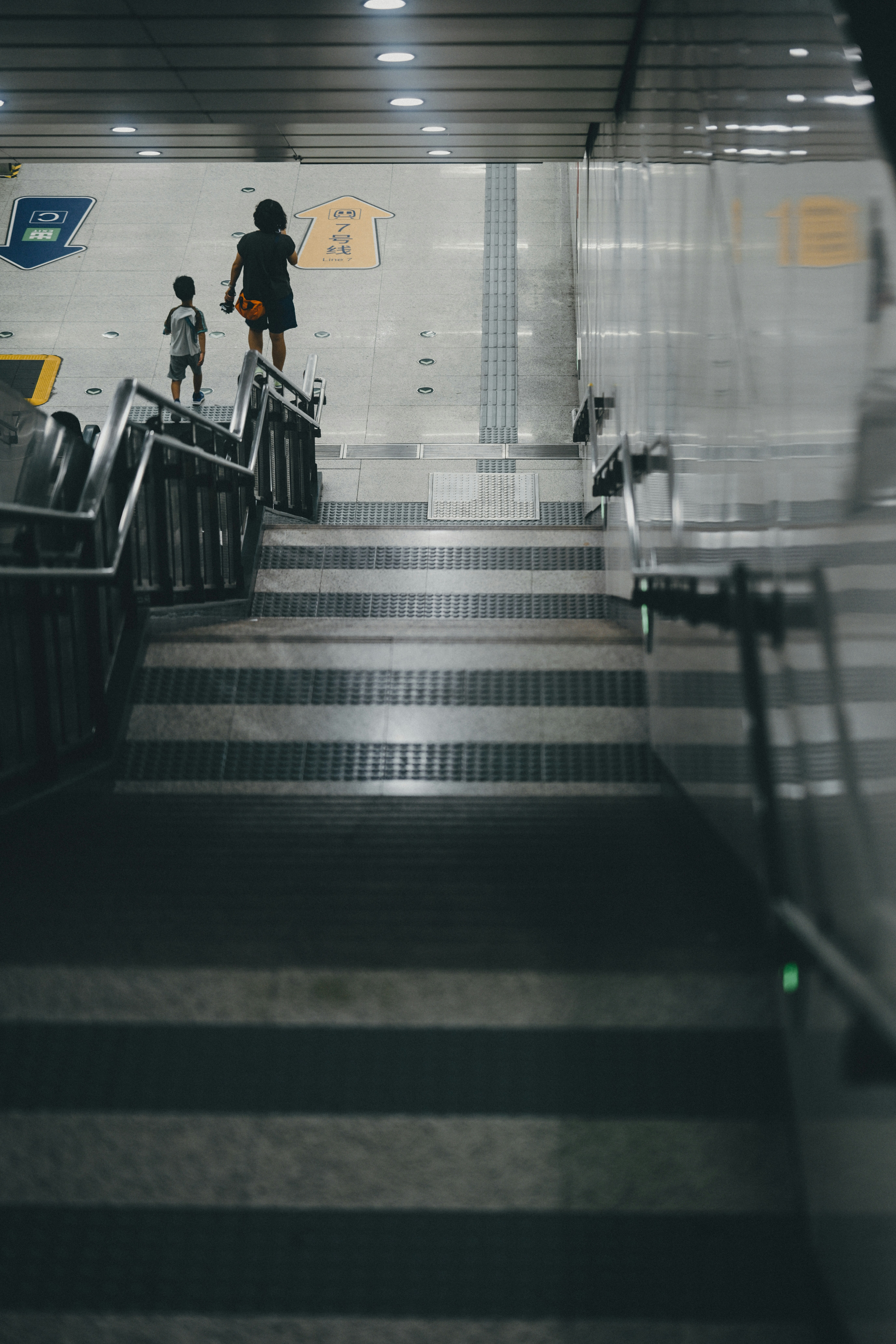 Two Figures at the Metro Stair: A Quiet Descent Toward Anonymity