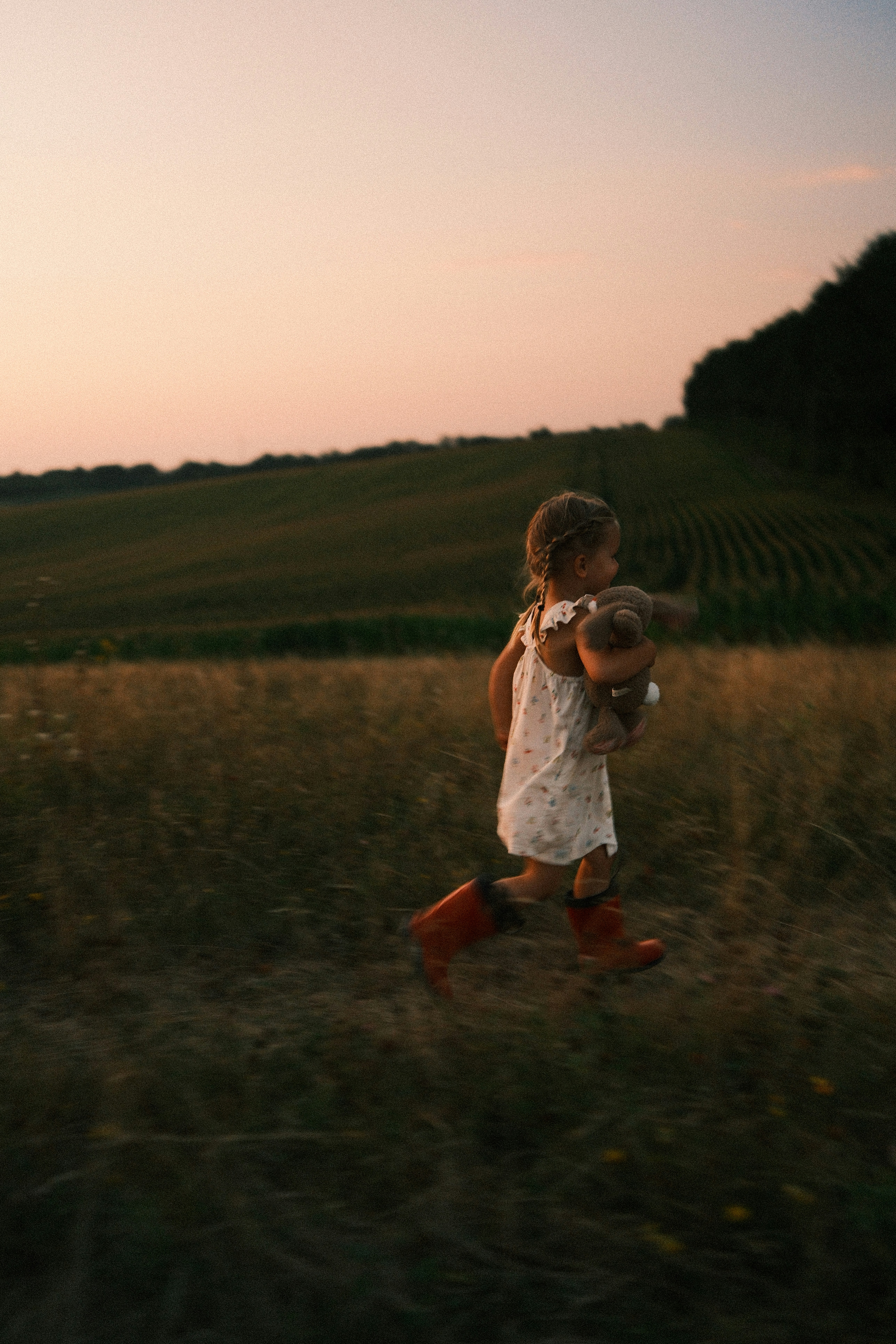 Child with a Toy Doll Crossing a Sunset Field