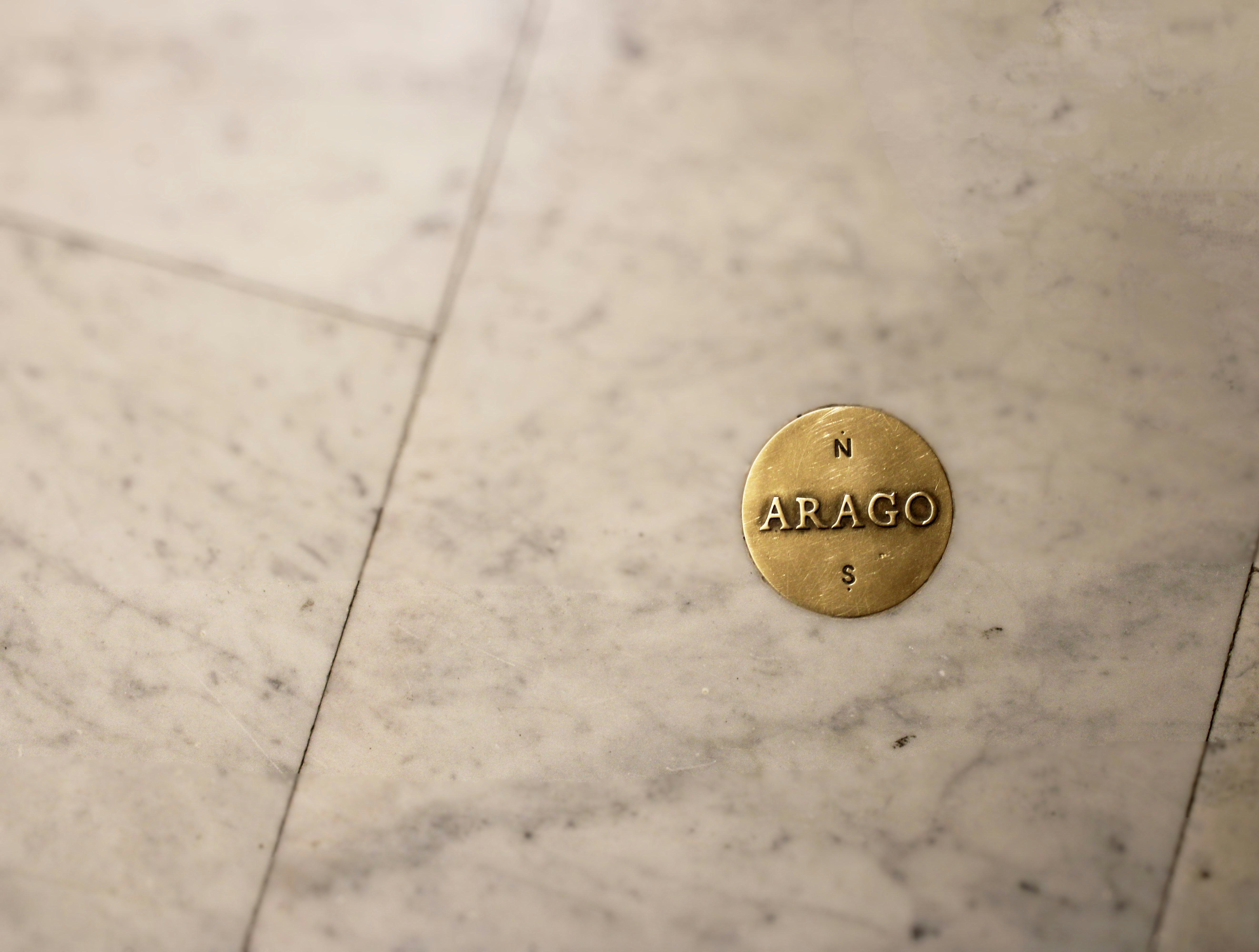 Marble Floor Compass: A Brass N-S-E Coin on Quiet Tiles