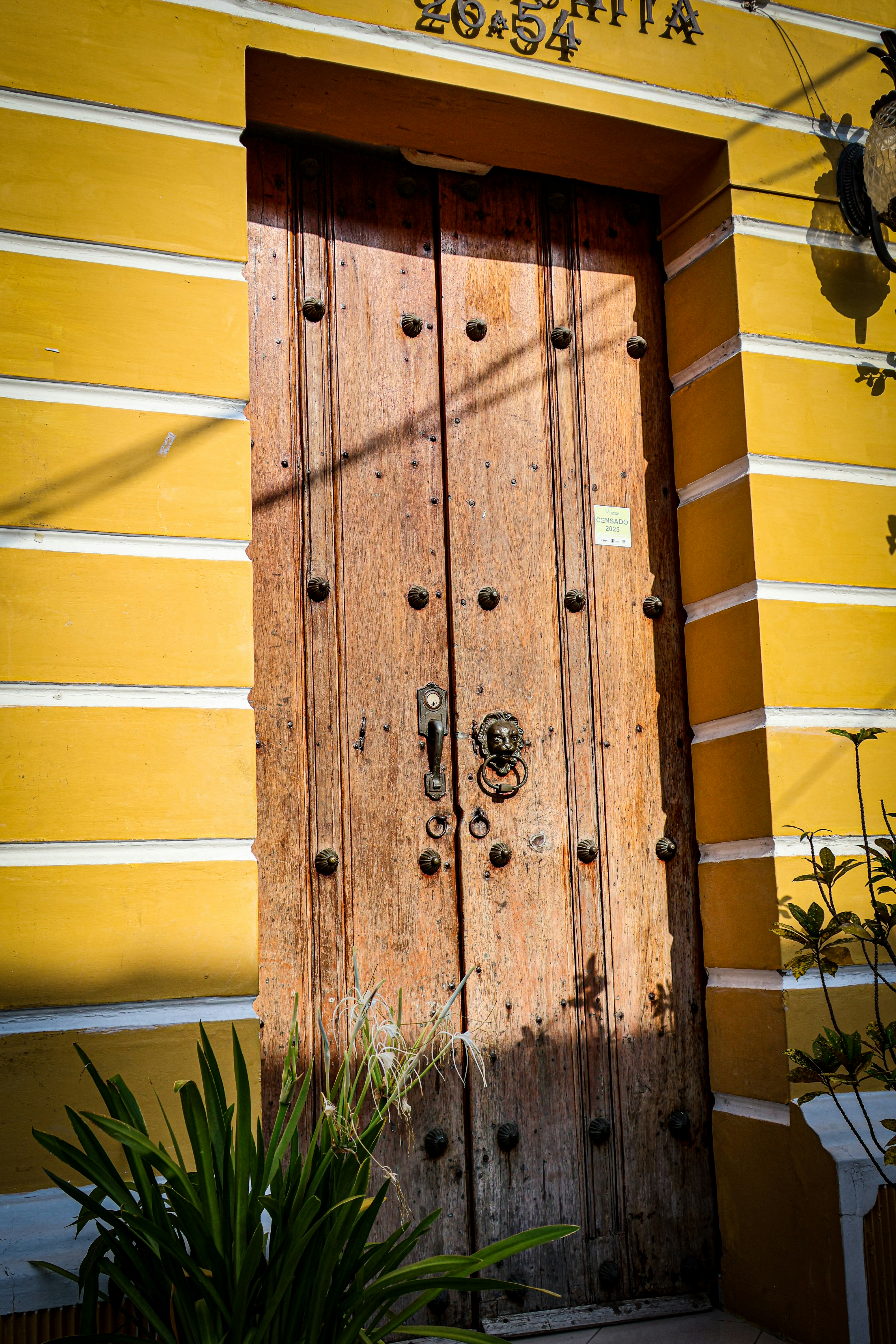 Weathered wooden door set in a sunlit yellow façade