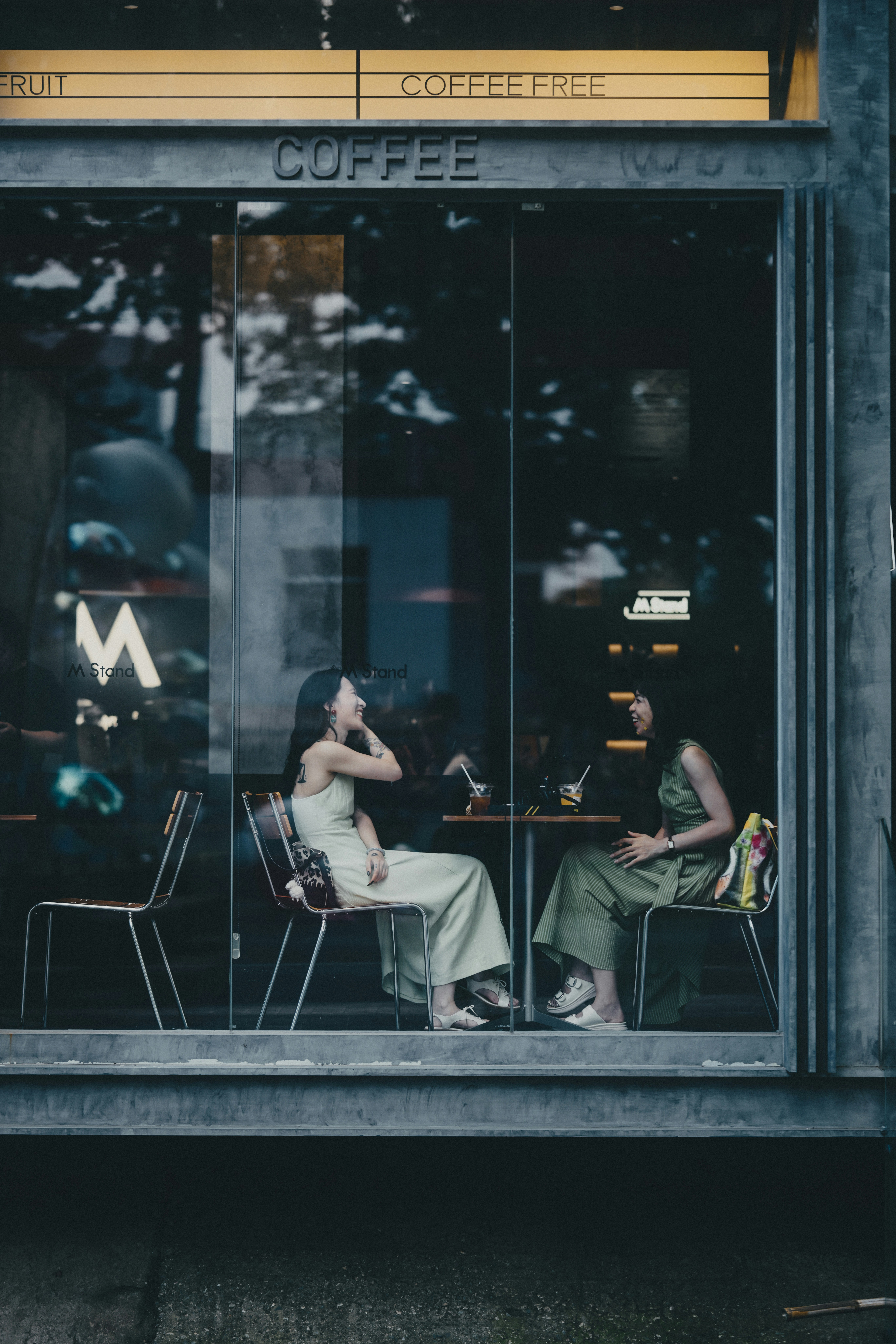 Cafe Conversation Through Glass: Two Women in Evening Light