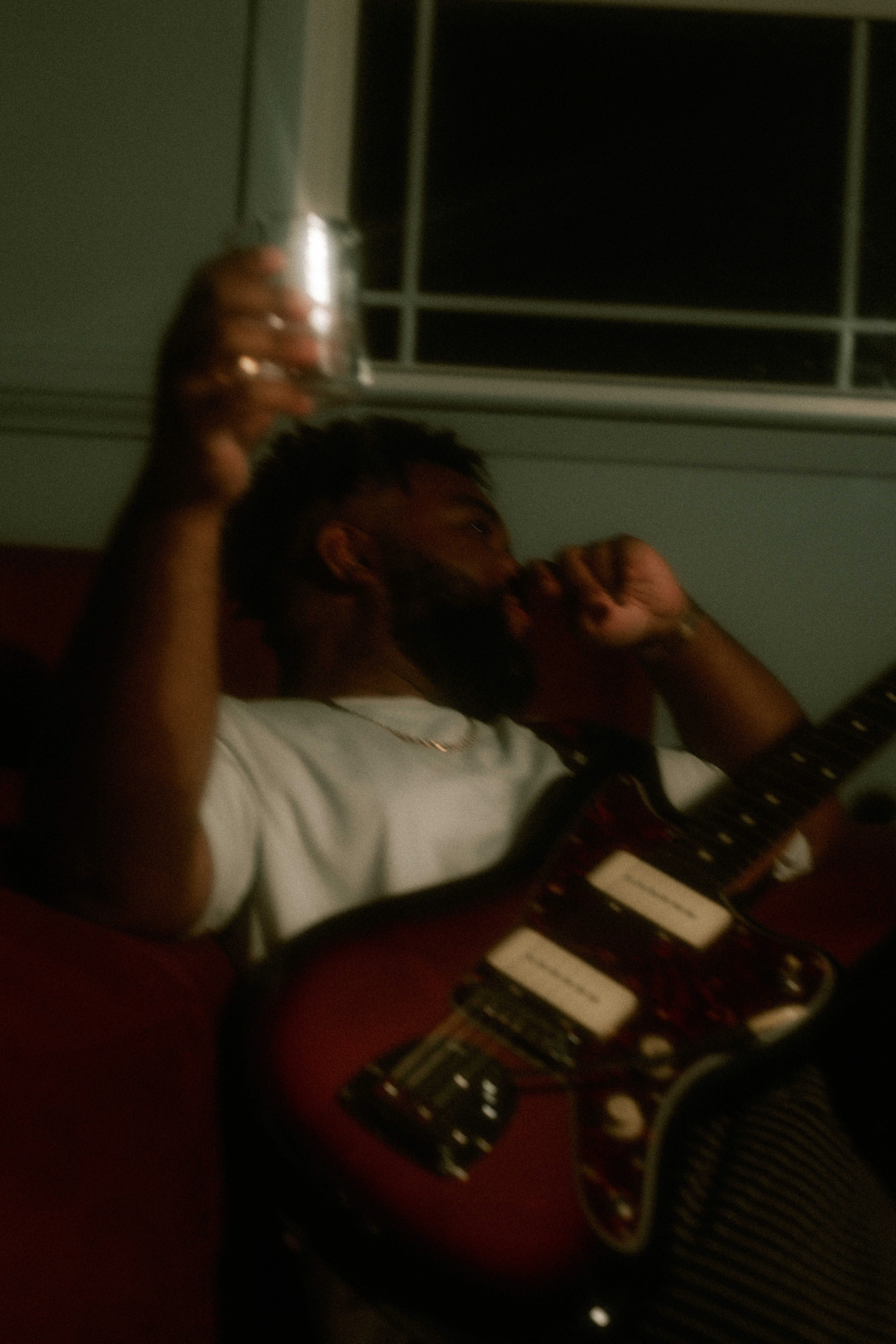 Midnight Jams: A guitarist raises a glass in the dim lounge glow