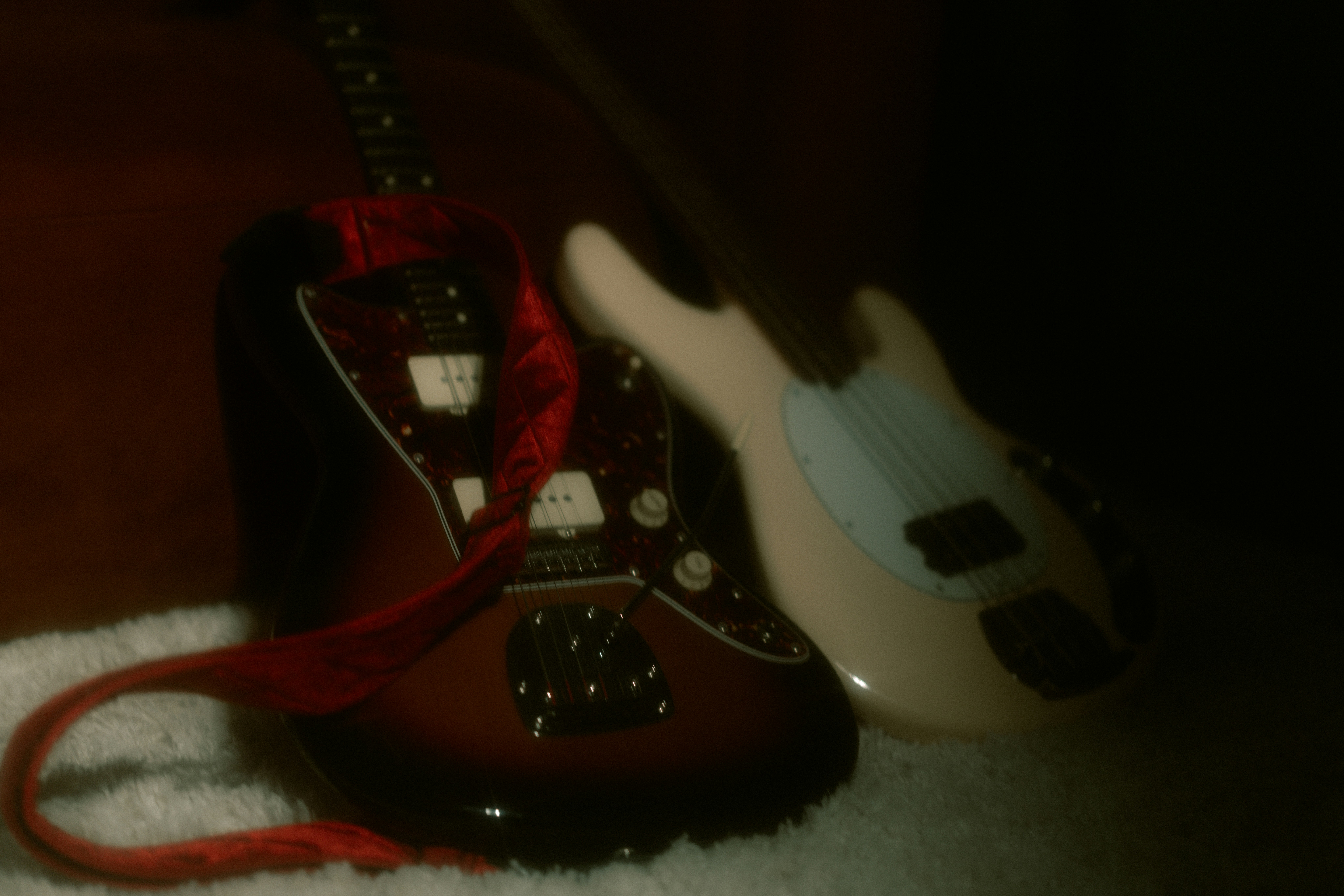 Dim Studio Harmony: A Red Telecaster and Cream Bass in Soft Focus