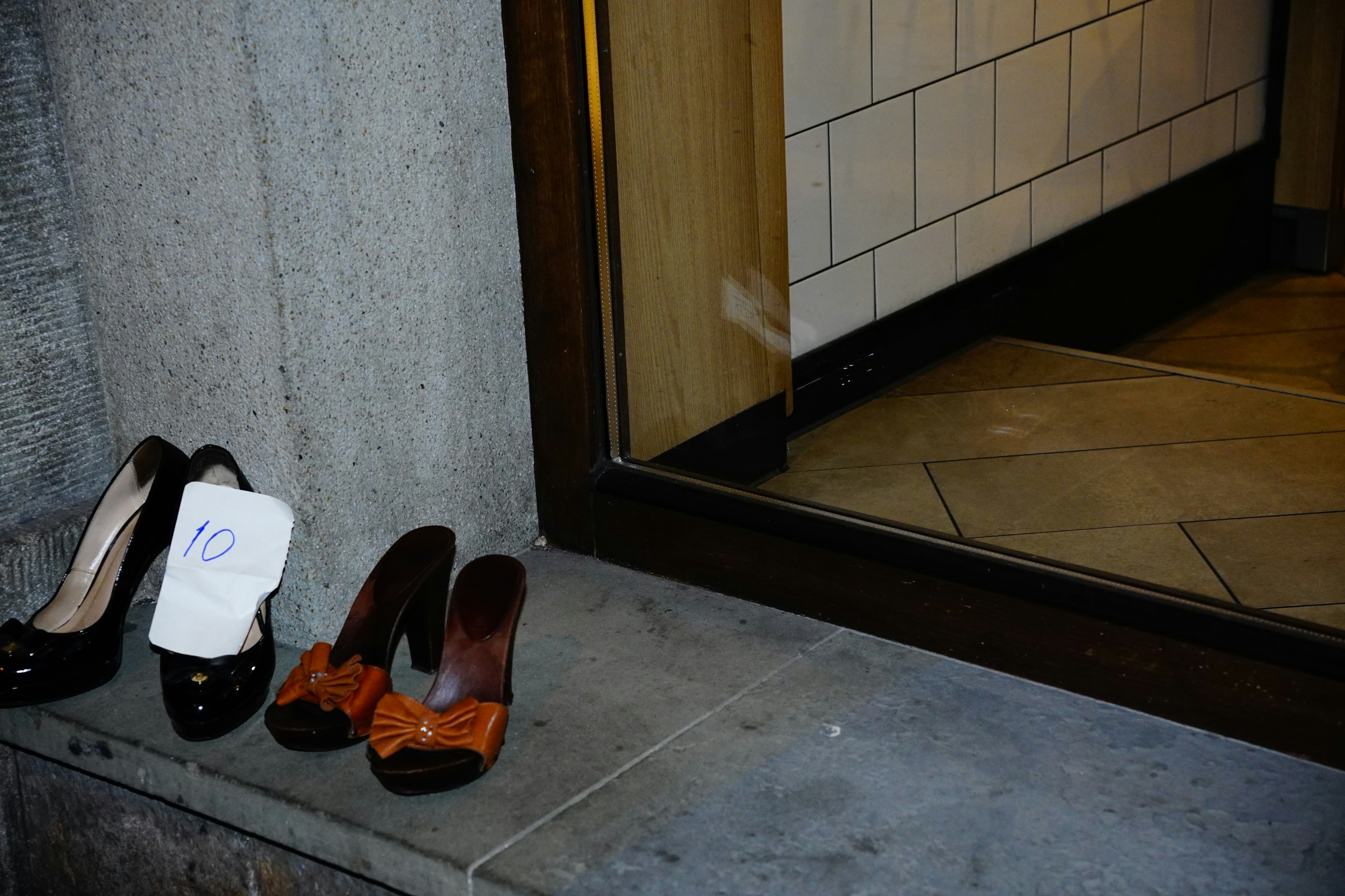 Three Shoes on a Concrete Threshold: A Quiet Street-Level Moment