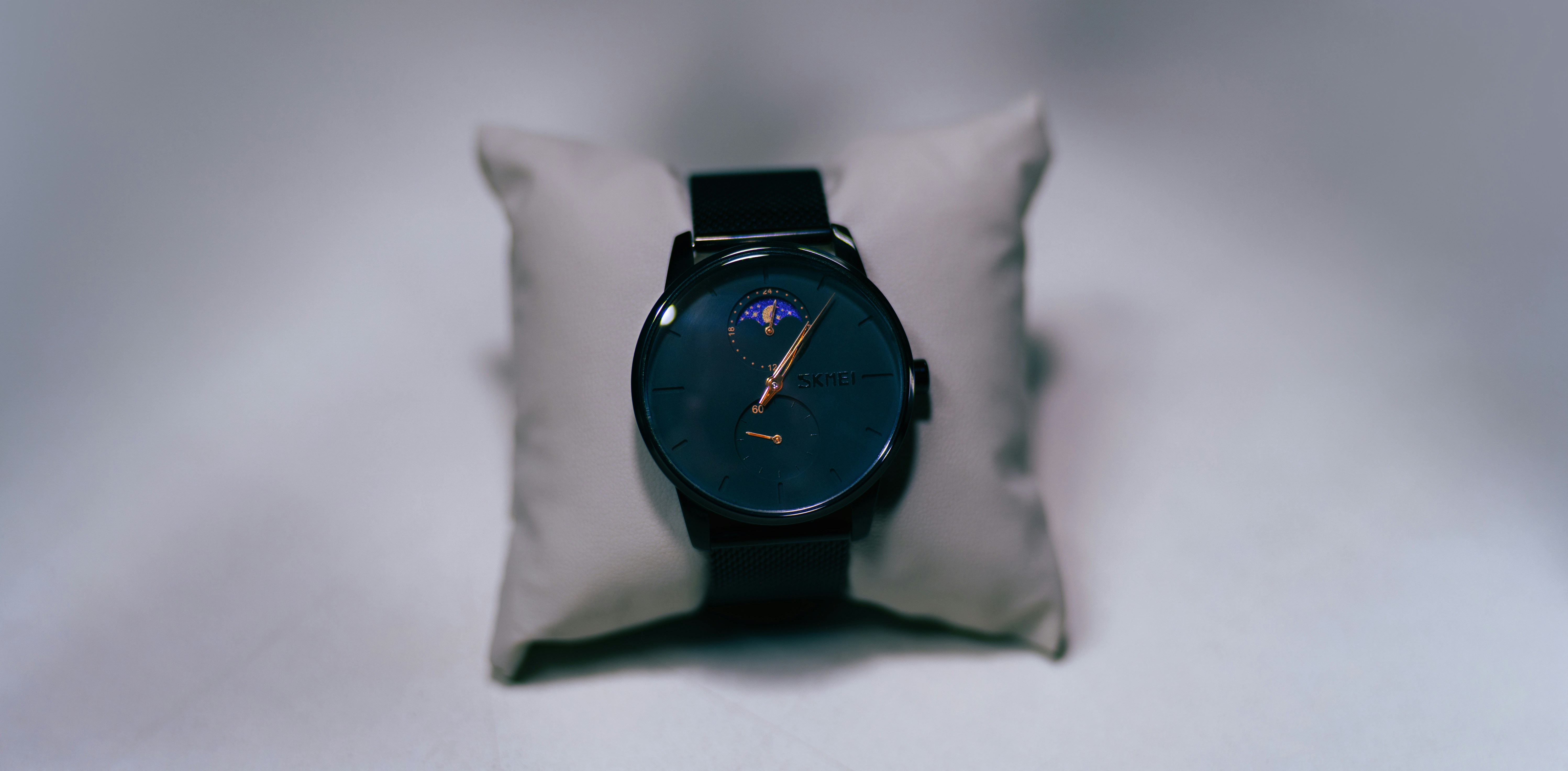 Midnight Orbit: A Sleek Wristwatch Resting on a Soft Pillowed Stage