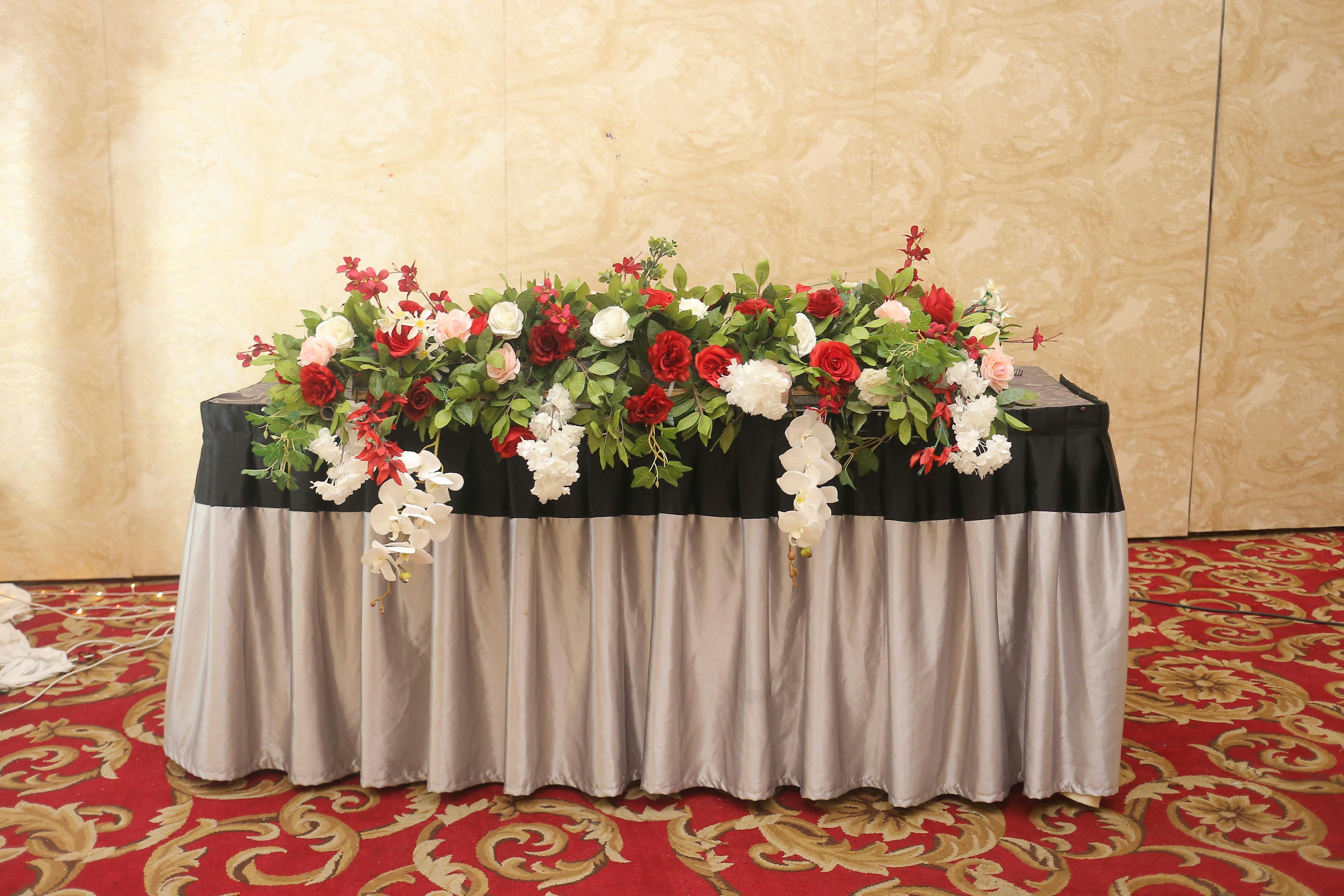 Floral wedding centerpiece resting above a satin-skirted table