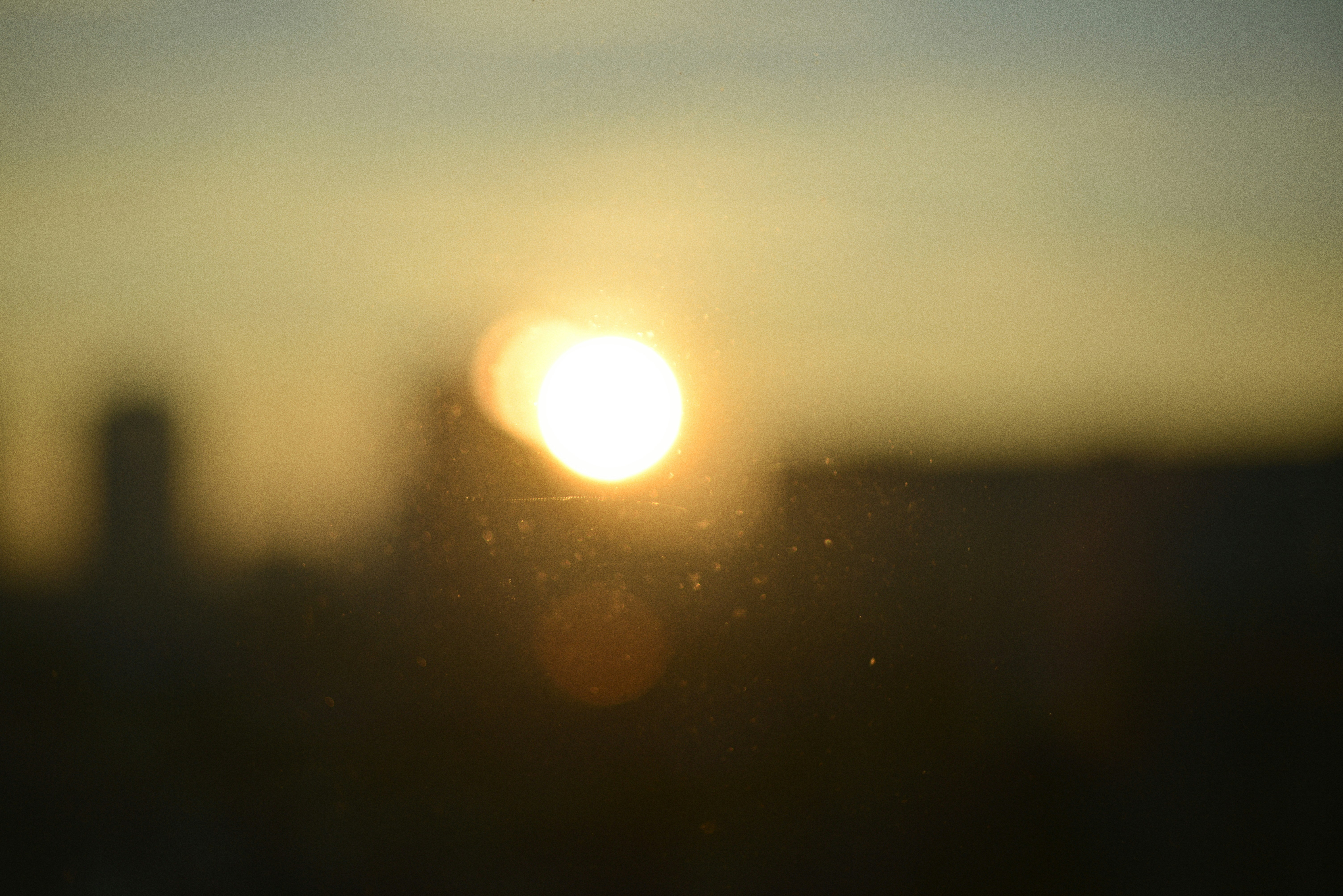 Sunlit Blur: A Quiet Sunset Over Distant Rooftops