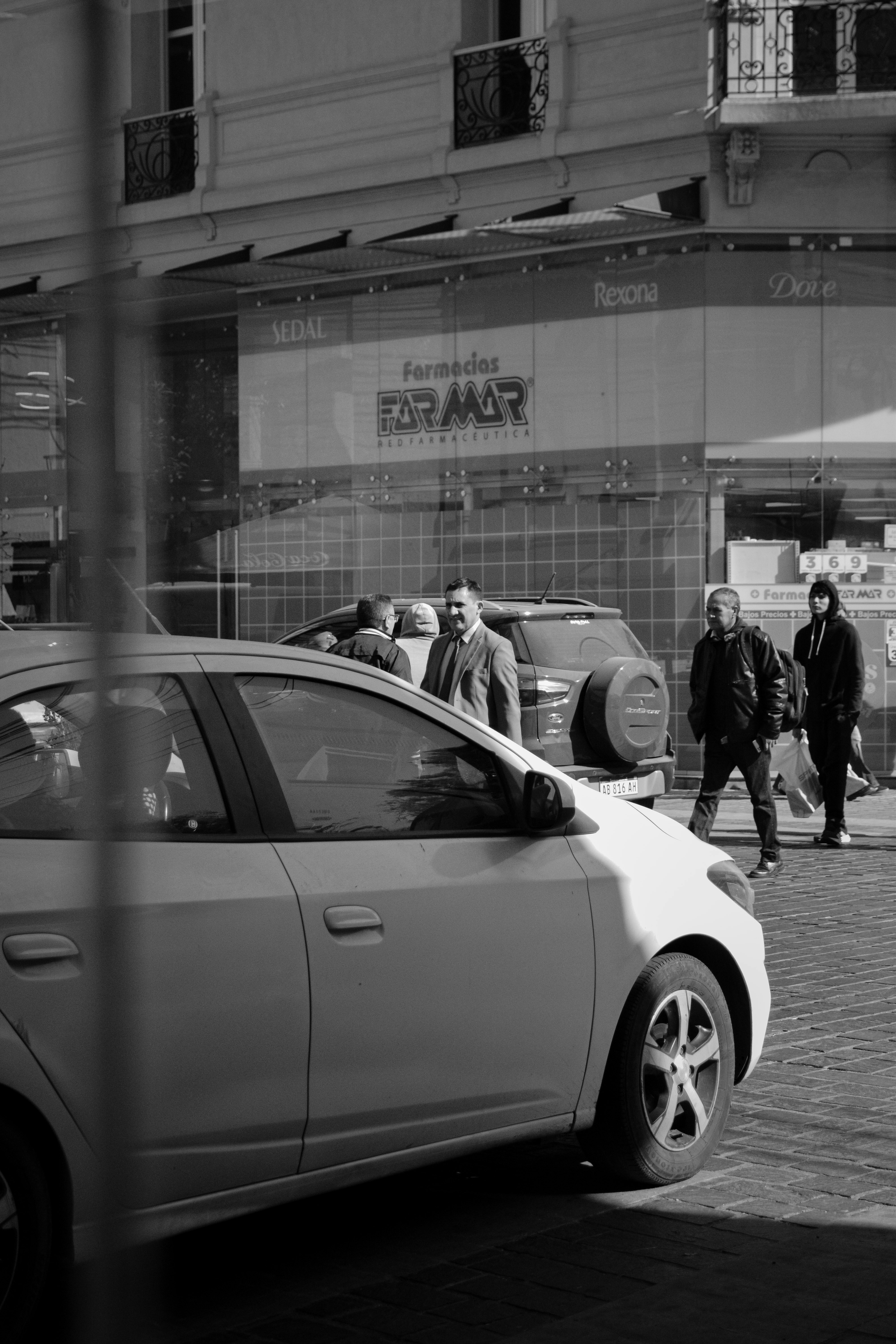 Street Portrait in Motion: A Sunlit Scene Behind a Parked Car
