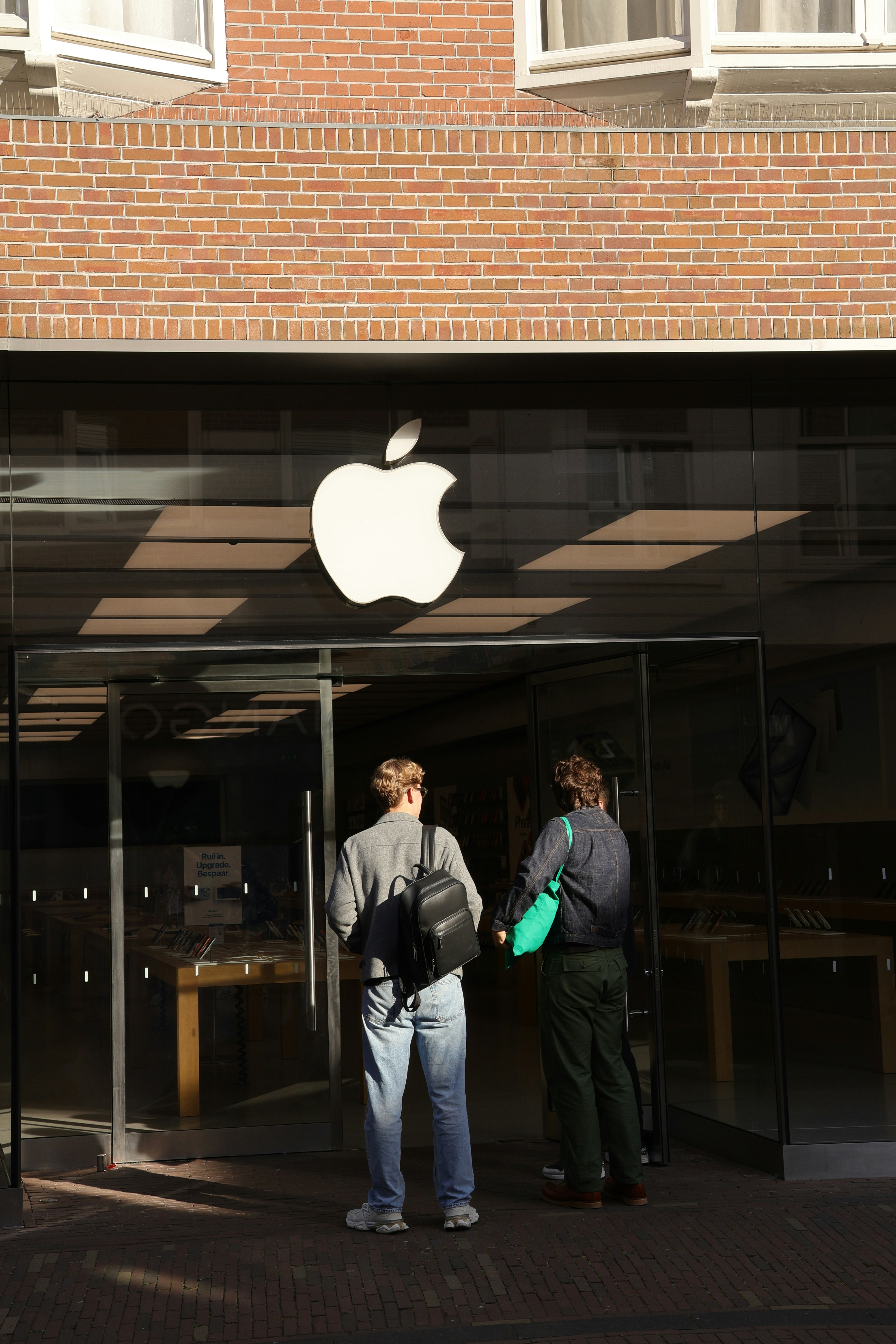 Apple Store Entrance: Two Visitors Converge Under a Glowing Logo