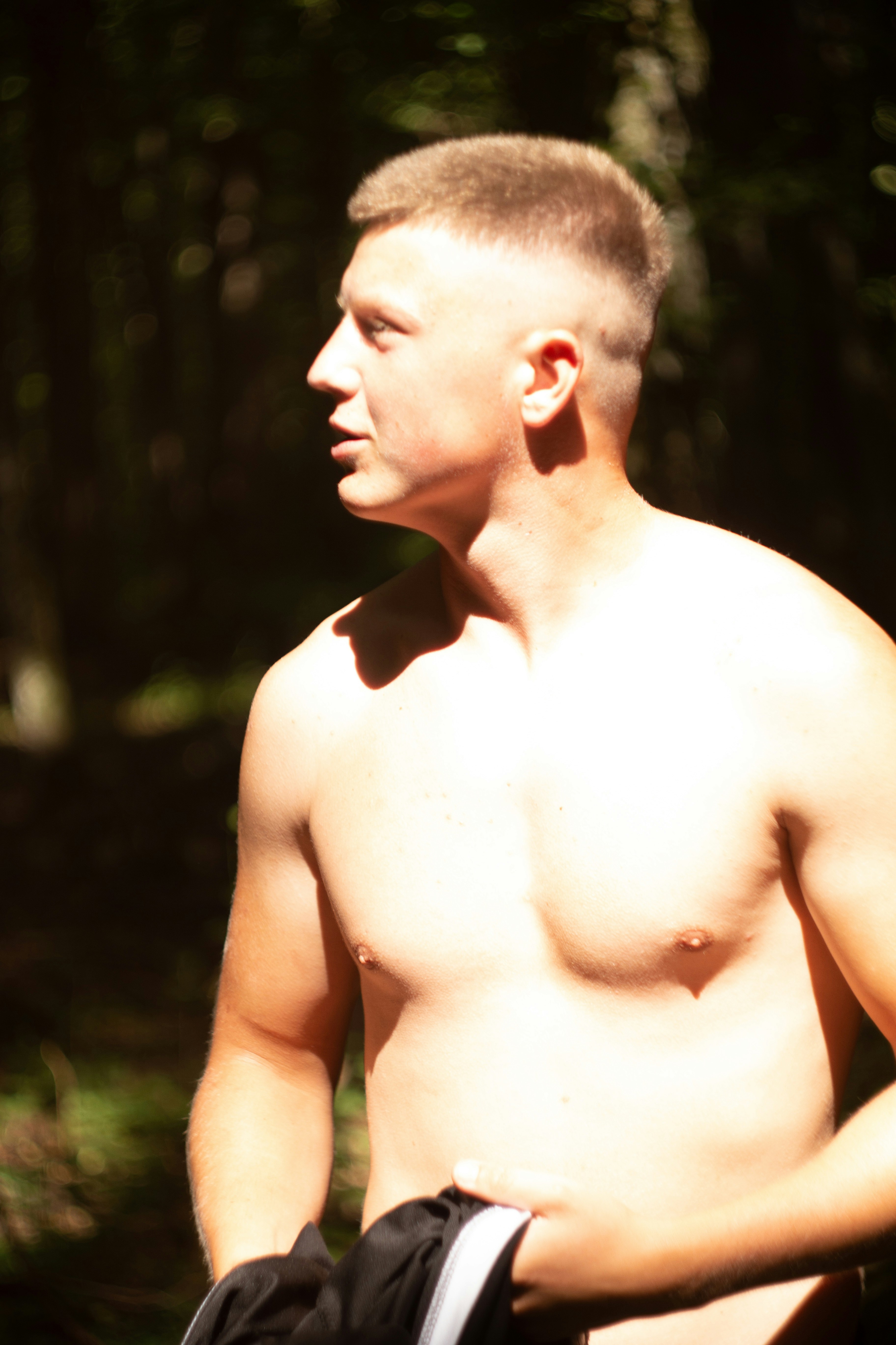 Sunlit Profile: A Shirtless Portrait in Dappled Forest Light