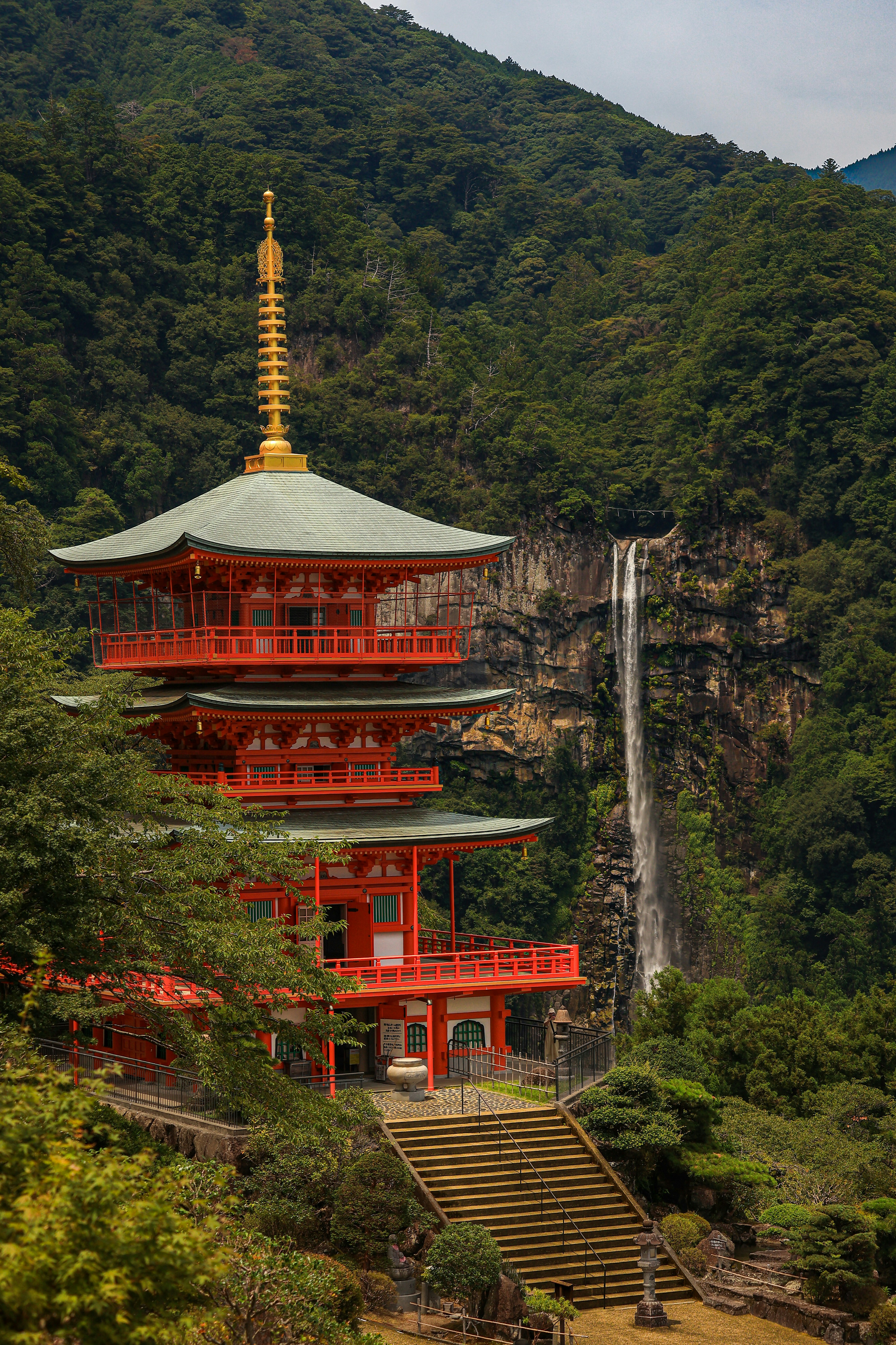 Crimson Pagoda in Hushed Green: A Tranquil Temple by a Waterfall