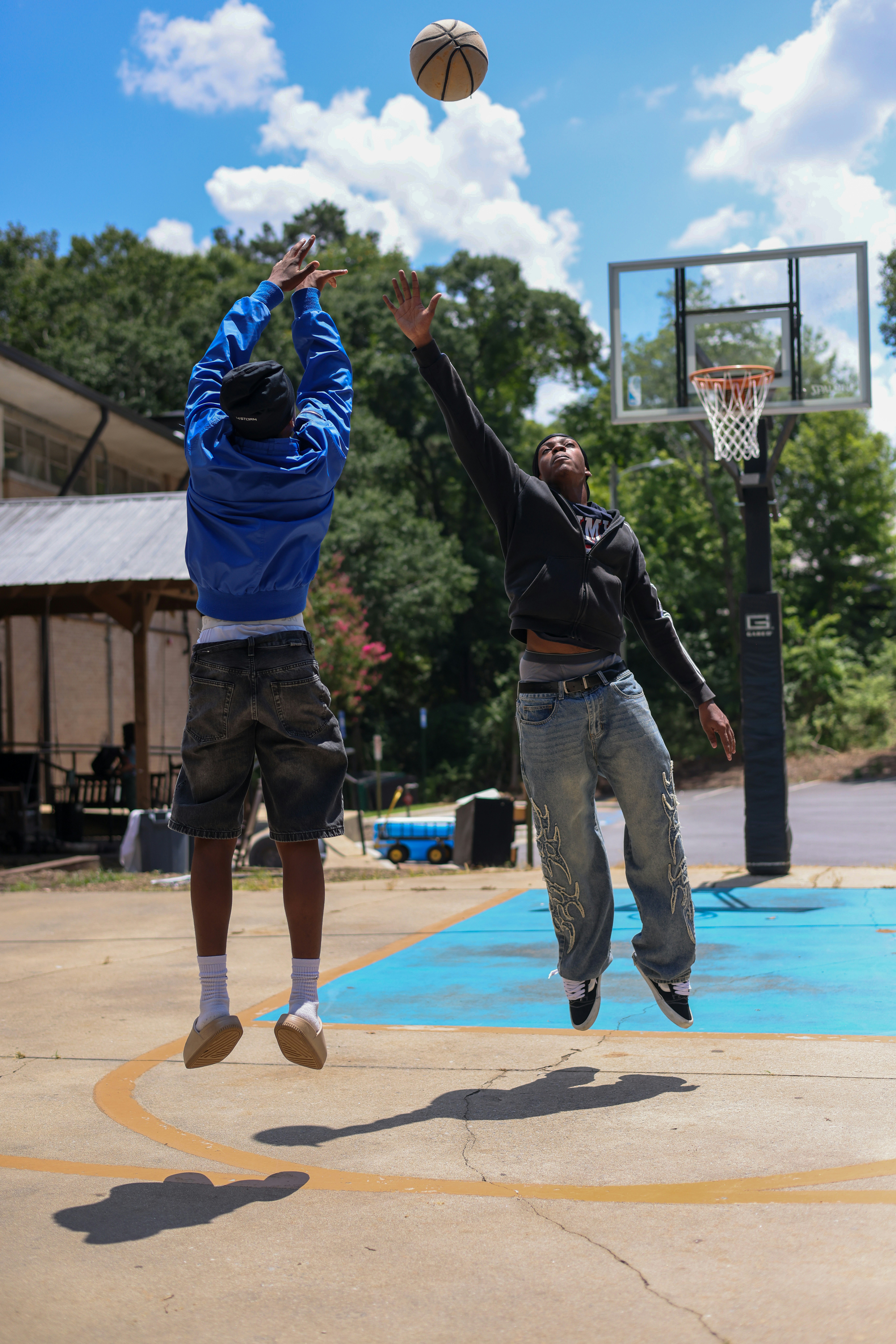 Two Jumpers Chase the Basketball Under a Clear Sky