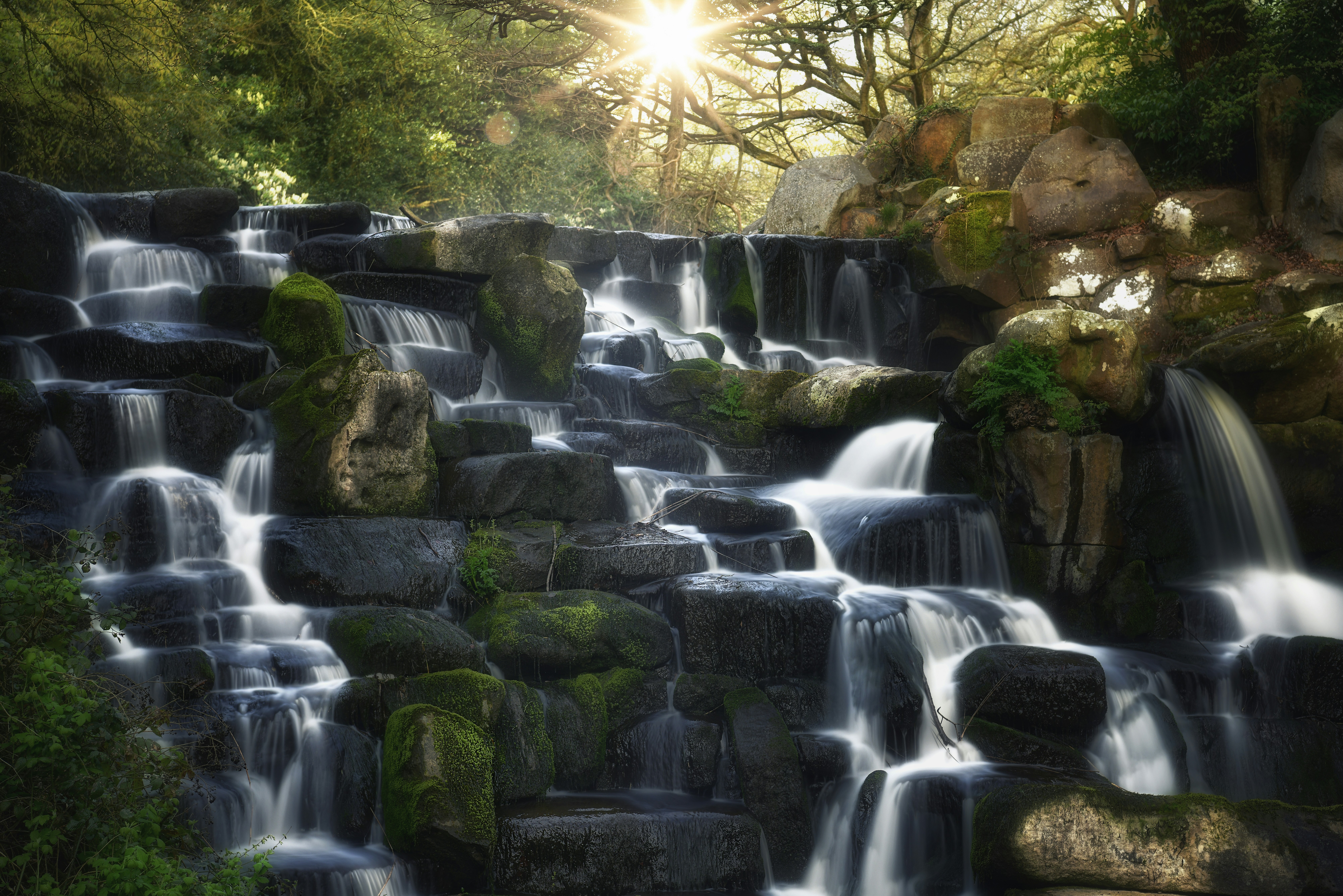 Golden Cascade: Sunlit Steps through Mossy Volcanic Rock