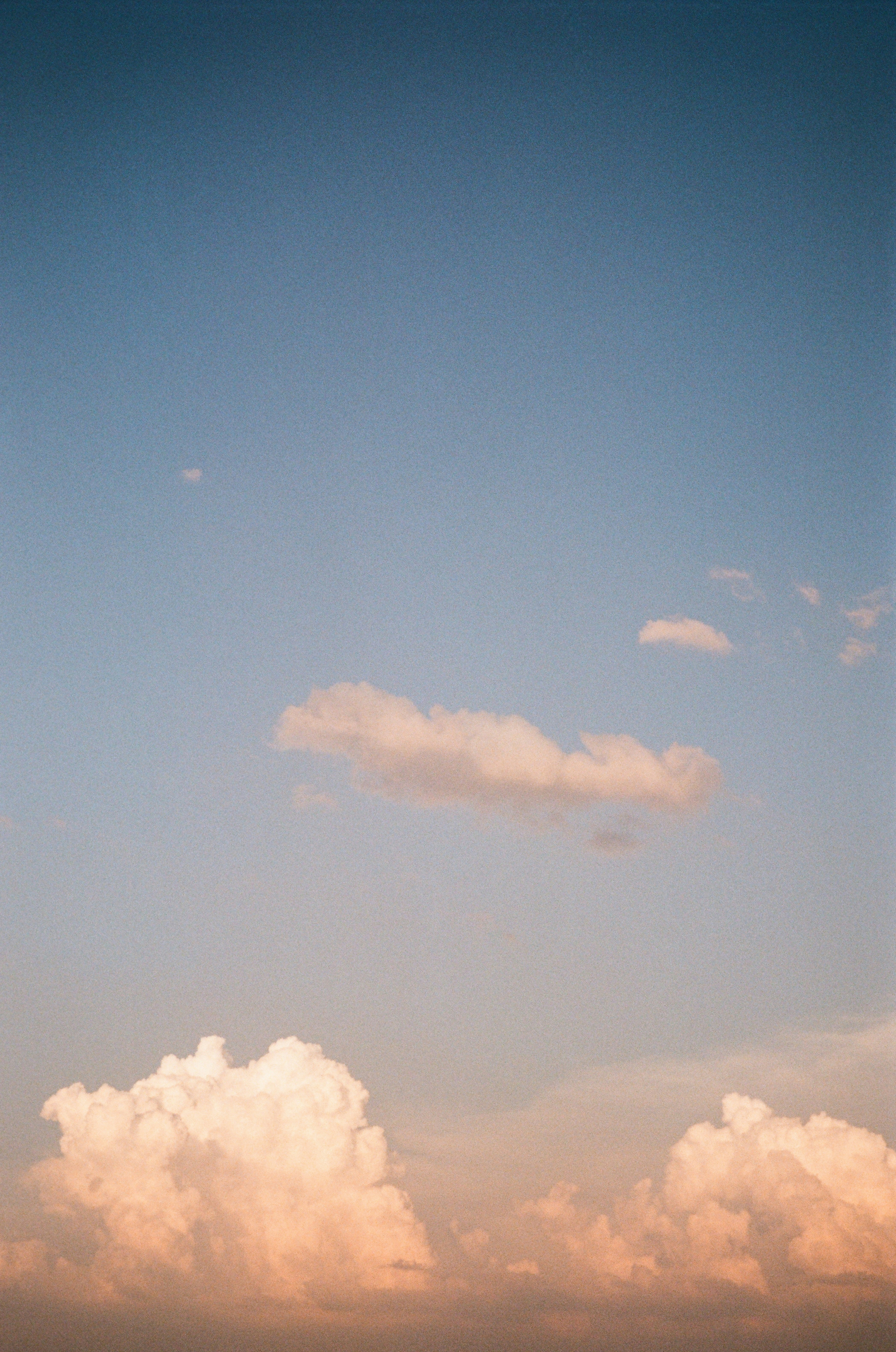 Soothing sky with warm clouds along the lower horizon, minimal composition focus on the tranquil gradient from blue to peach. This is a photograph of a serene sky scene.