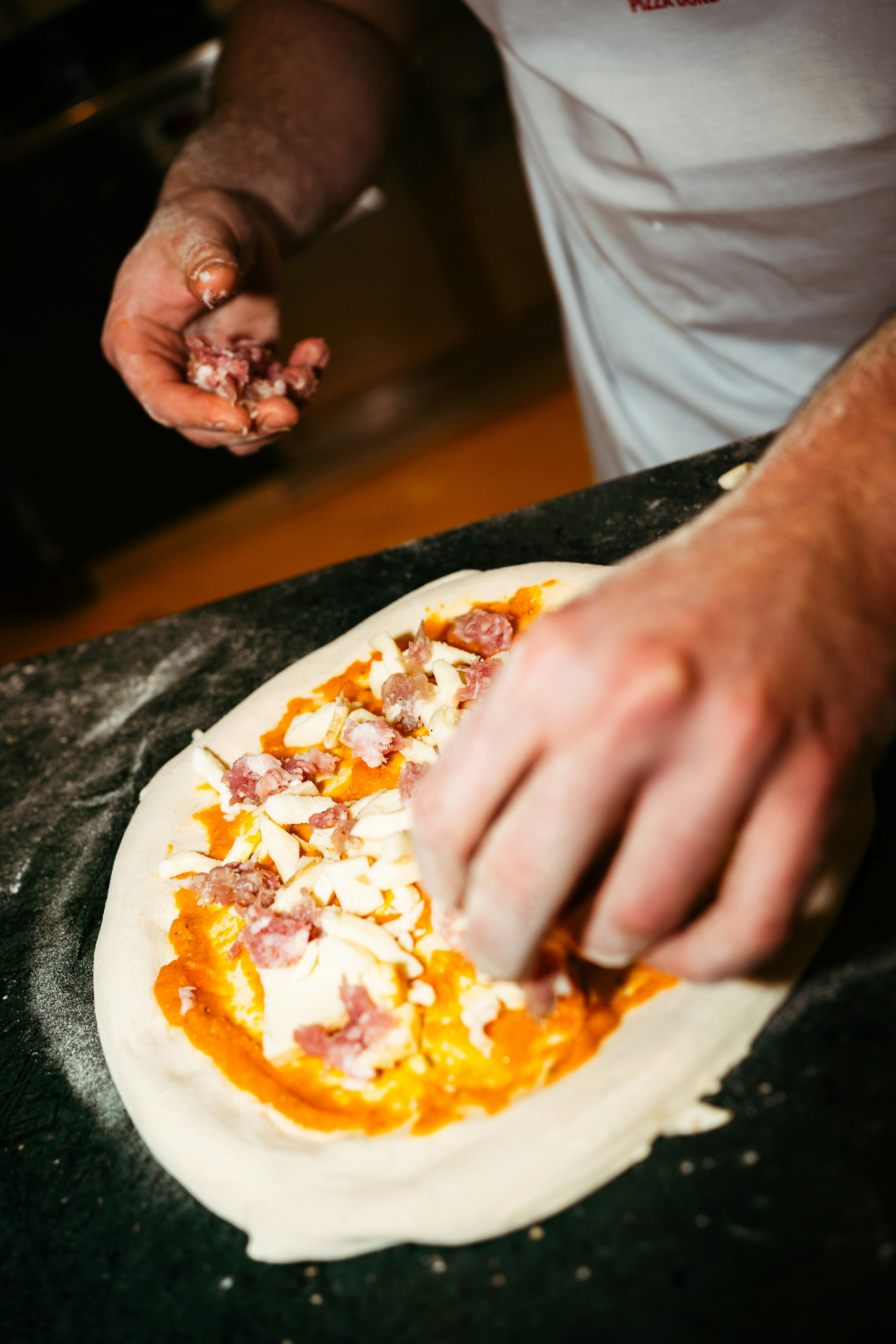 Hands at the Dough: Crafting a Pizza with Toppings