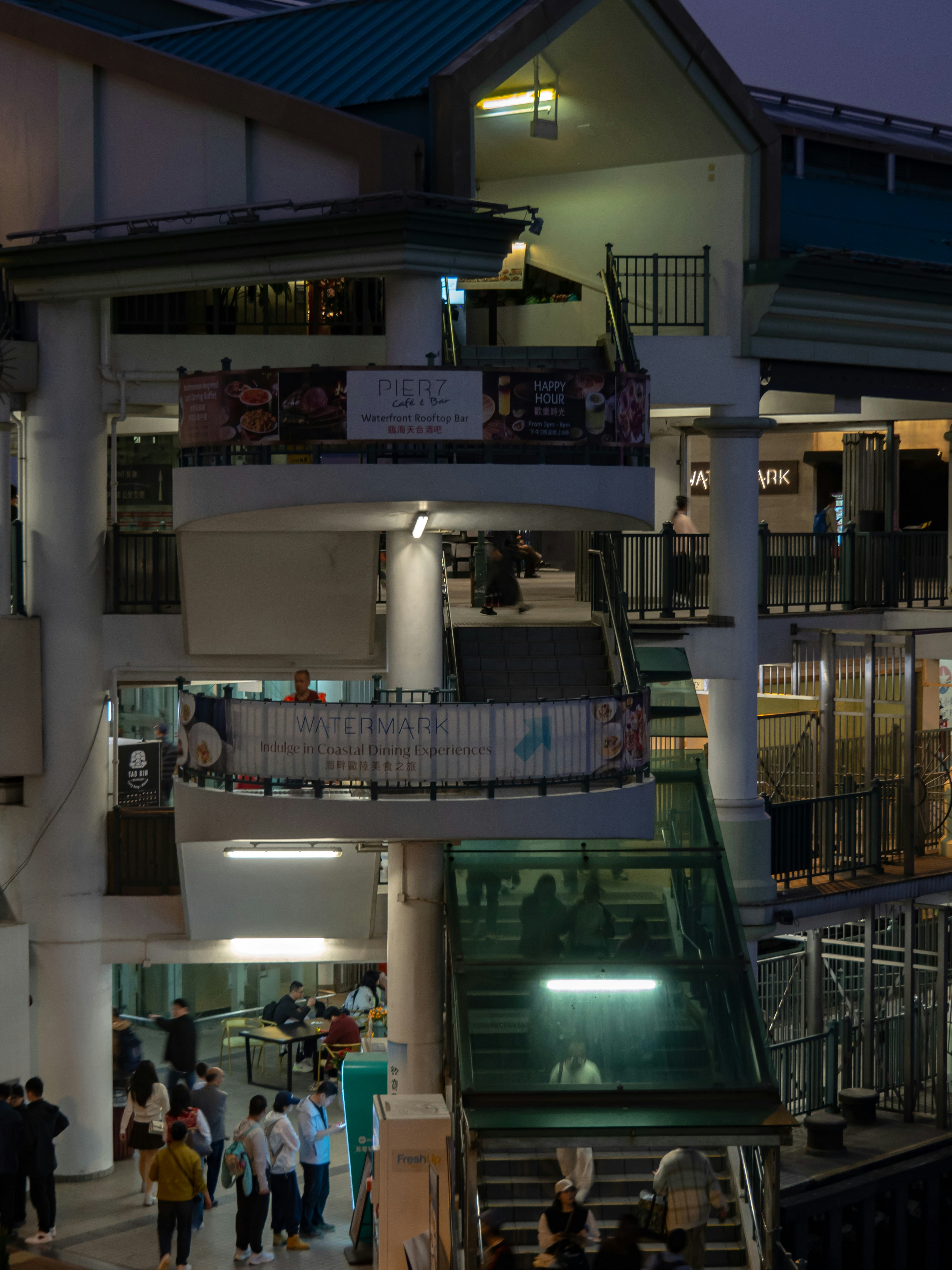 Midnight Atrium: People bustle through a sunlit multi-level shopping center