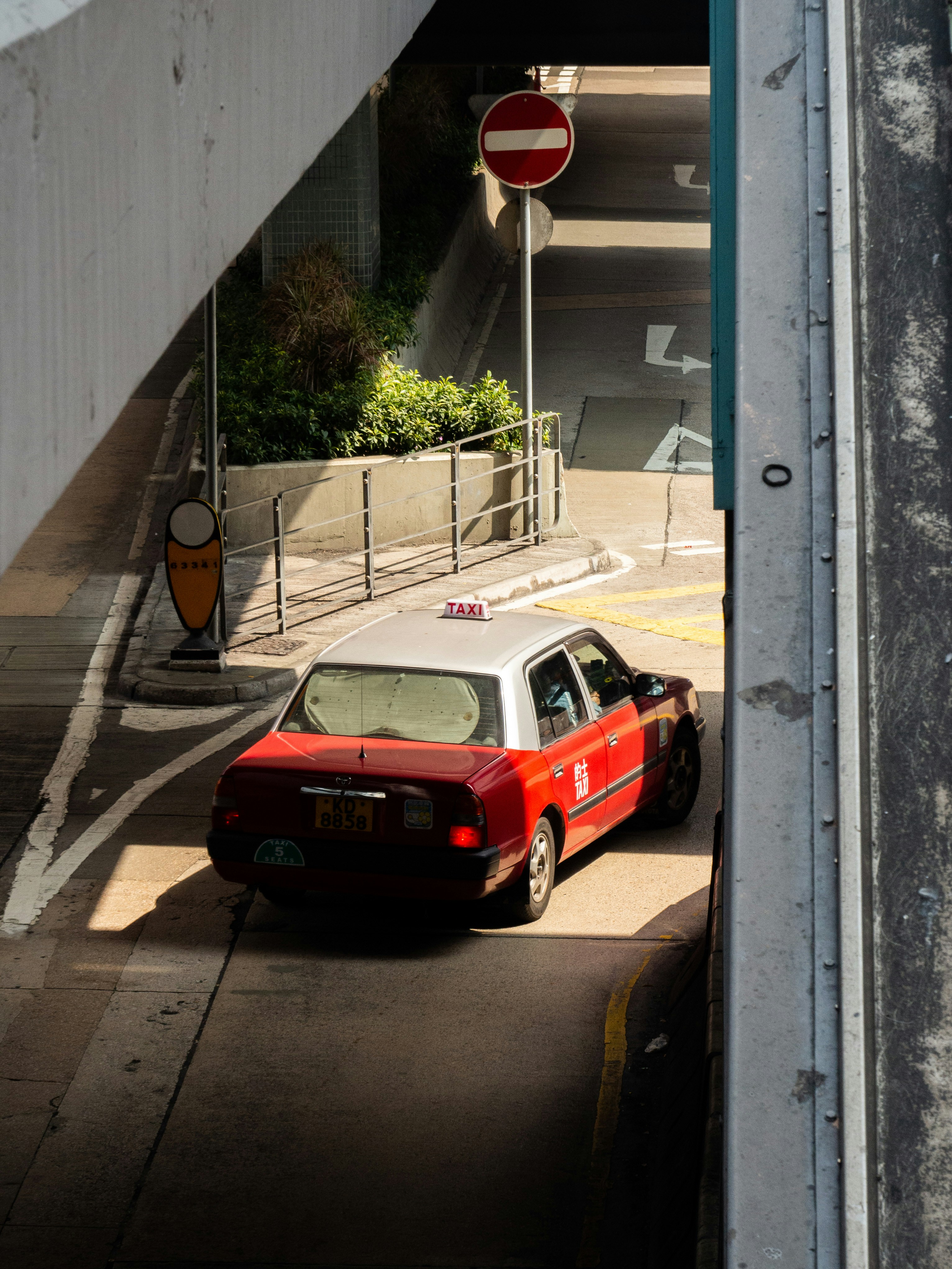 A Red Taxi Rounds the Corner Under a Concrete Overpass