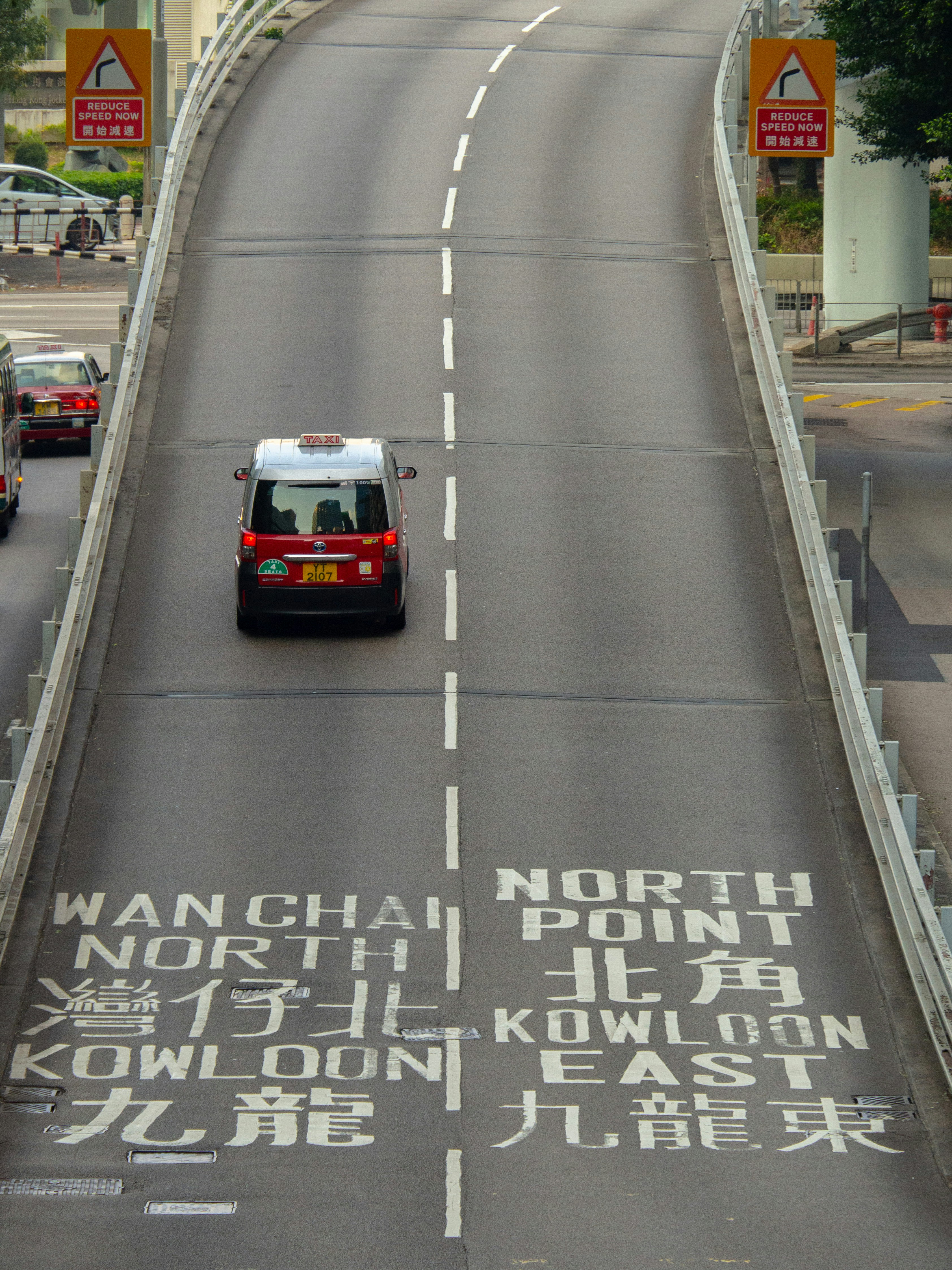 Raised roadway toward a gateway: a red van climbs a dual path