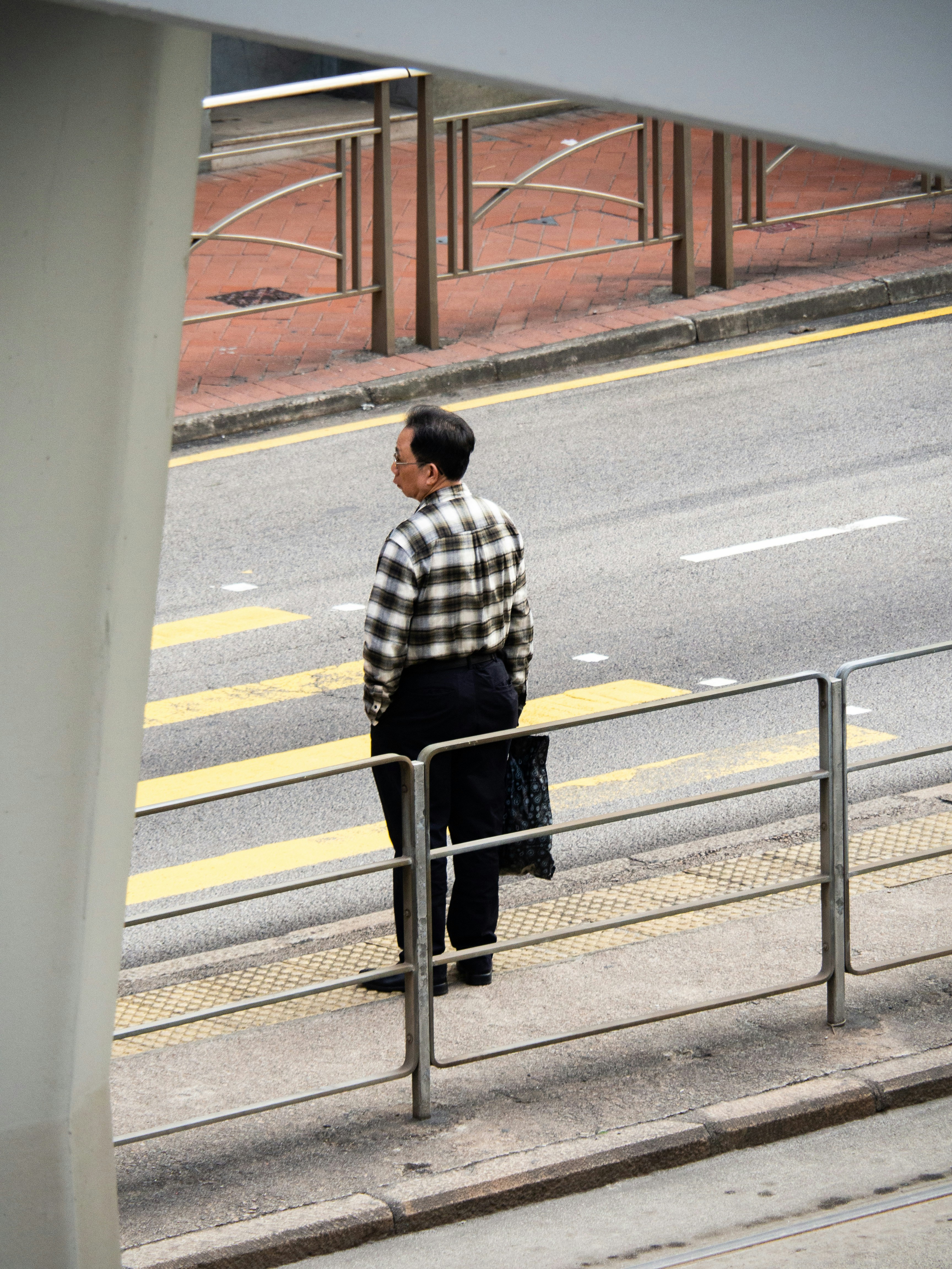 Man in Plaid Shirt Waiting by the Street Rail