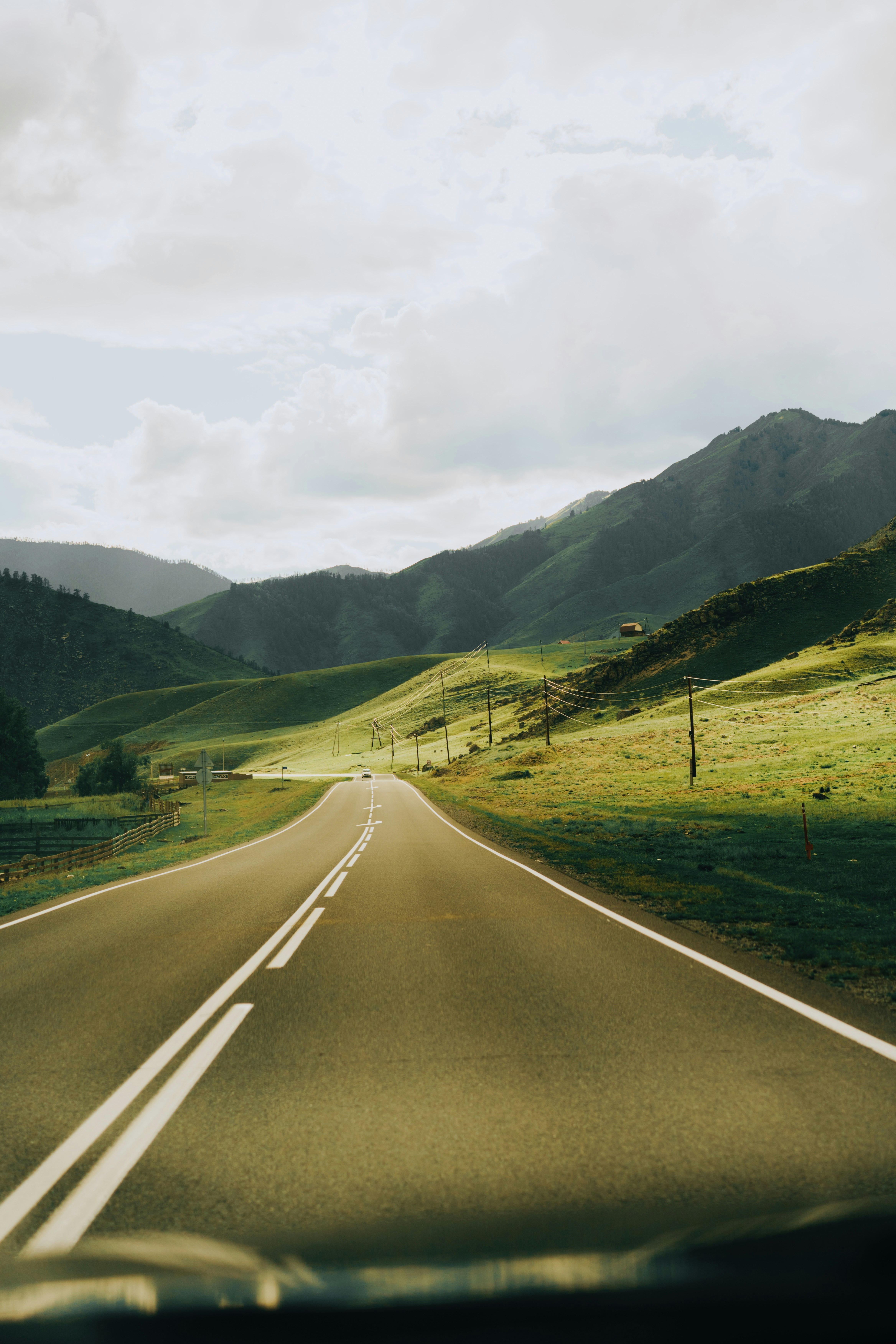 Open Road Through Green Hills Under a Soft Sky