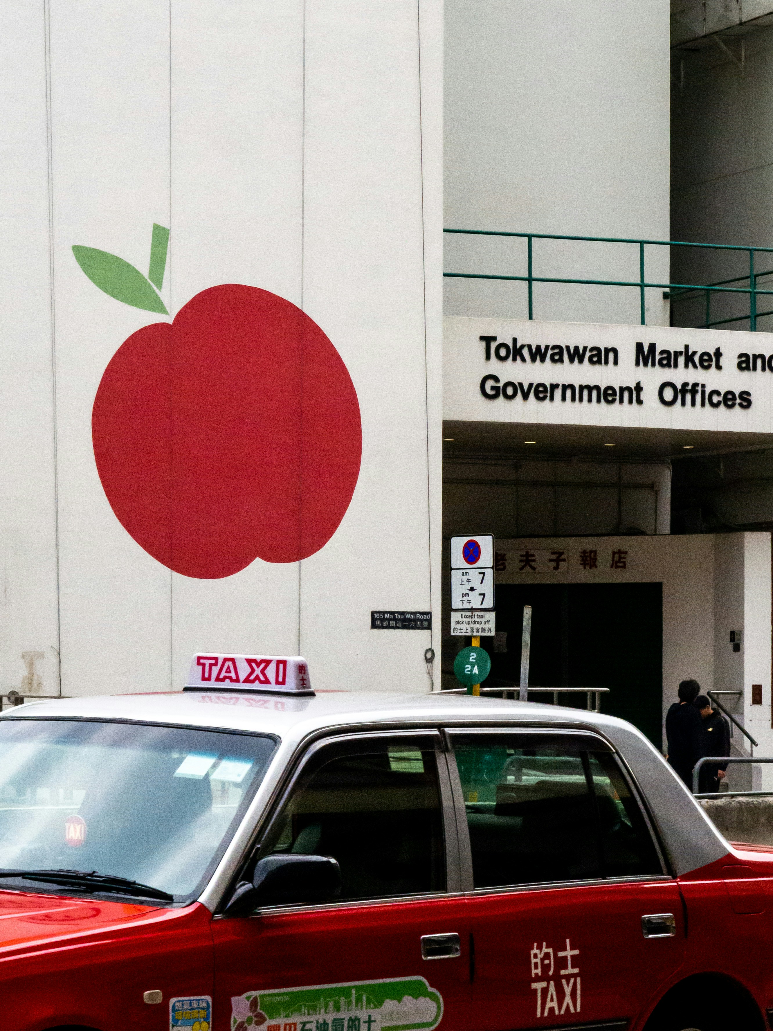 Red Taxi at the Apple-adorned Urban Facade