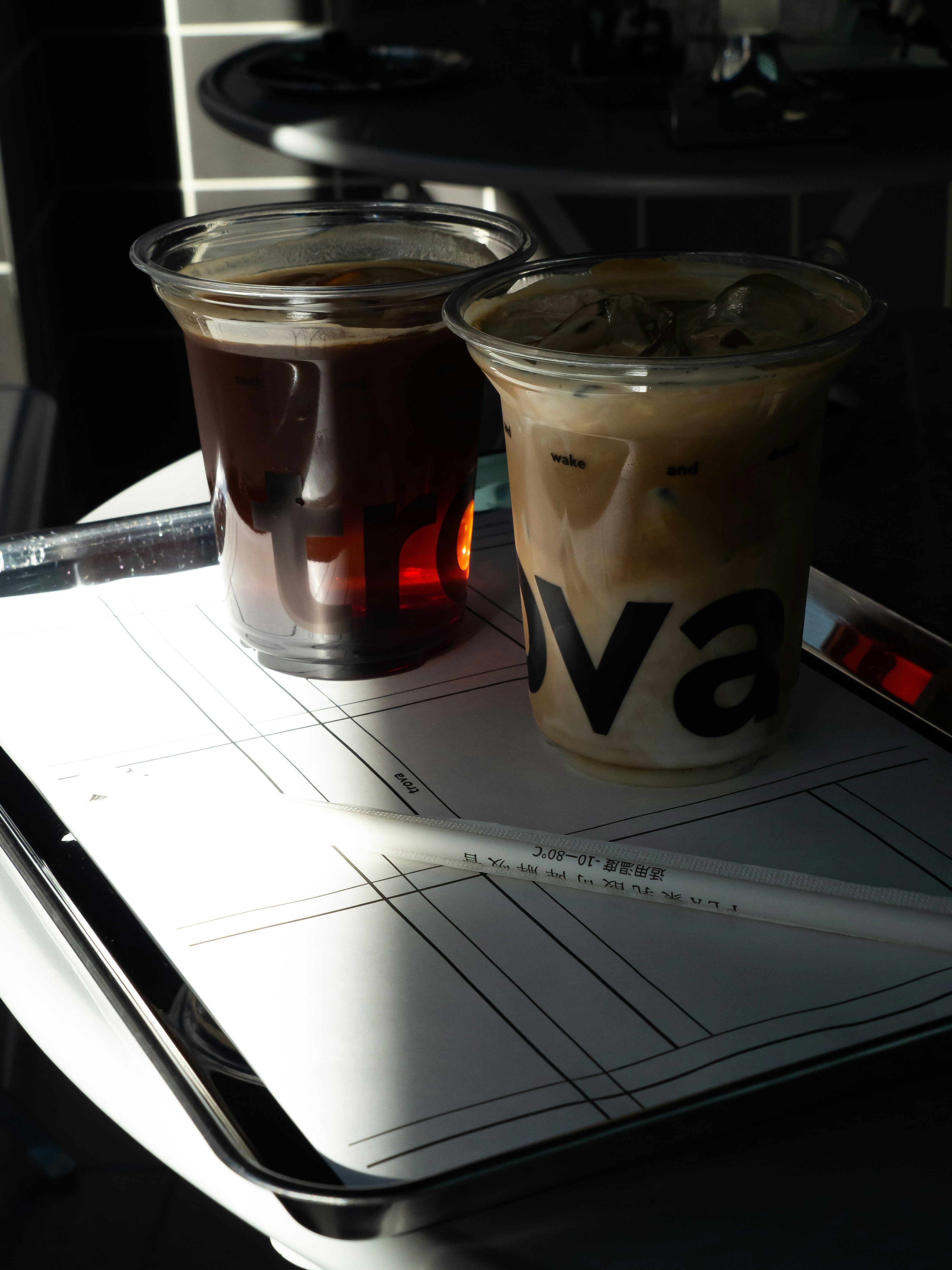 Two iced coffees in a sunlit cafe corner resting on a tray