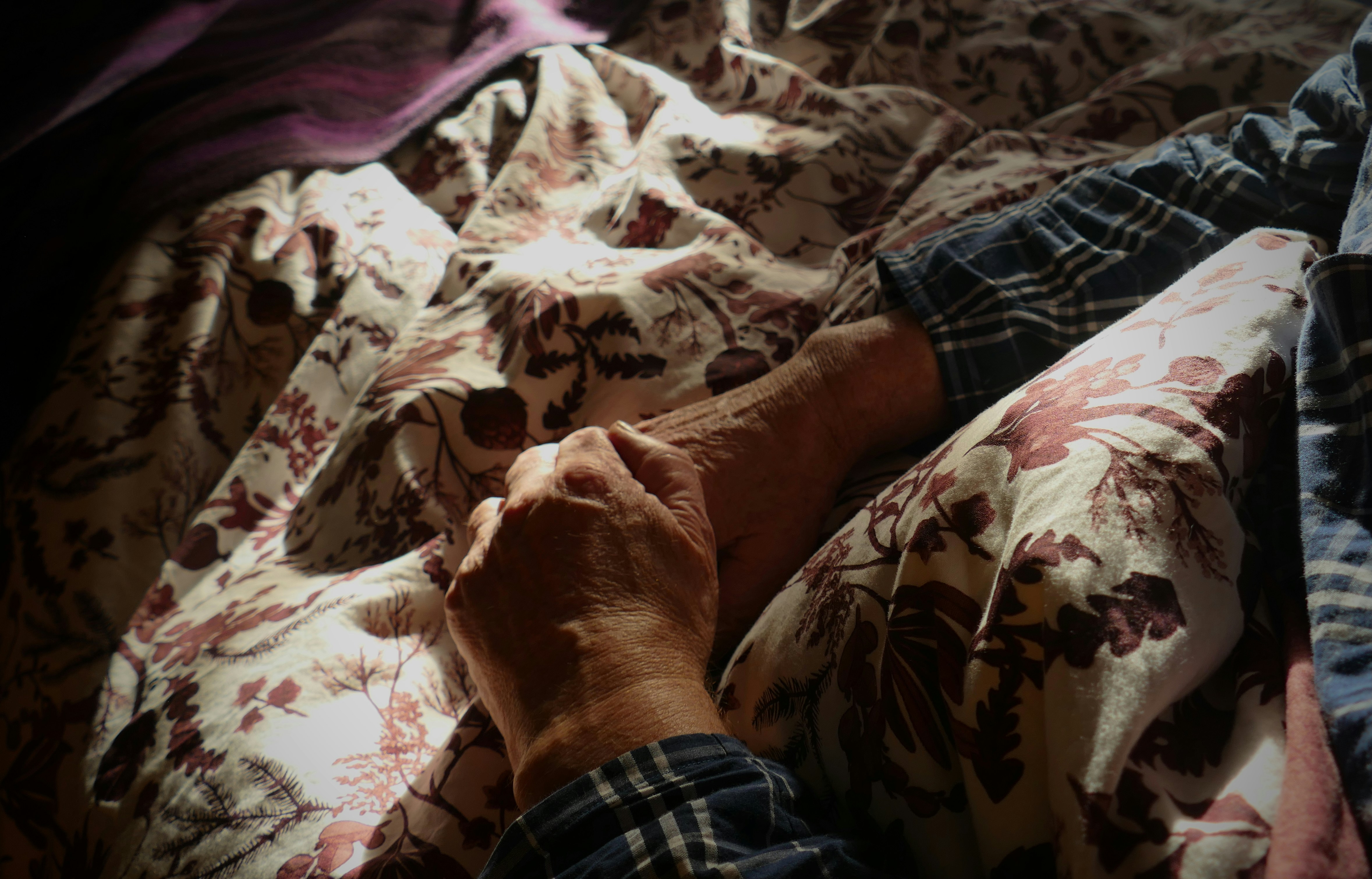 Interwoven Hands Resting on a Floral Quilt