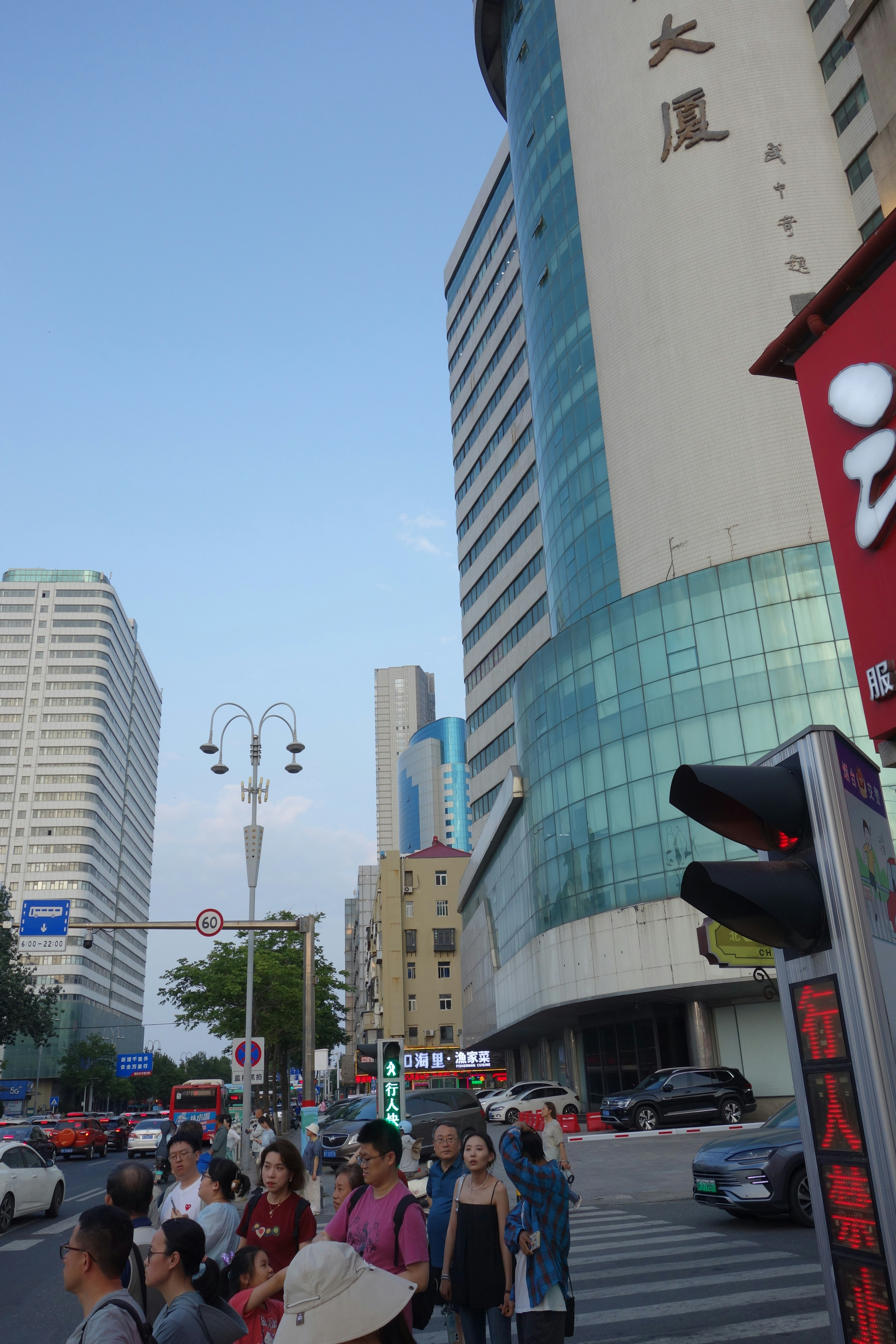 Urban Convergence: People Cross a Busy Street Before a Curved Glass Tower