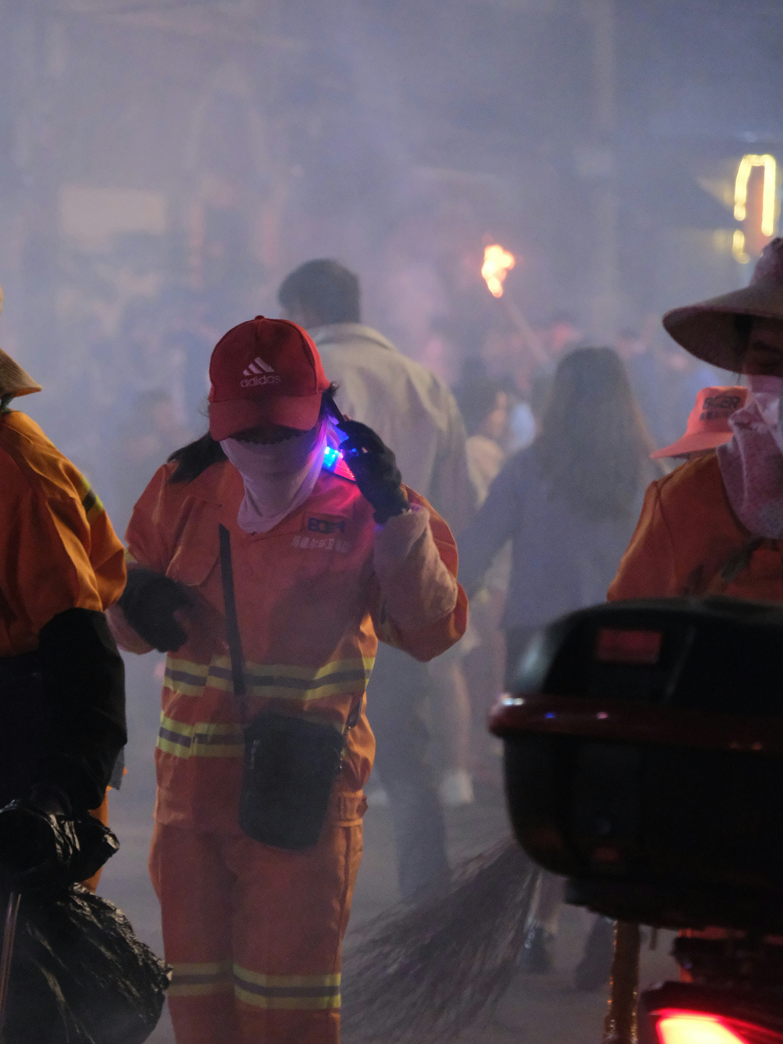 Masked responder in hazy aid station under orange glow