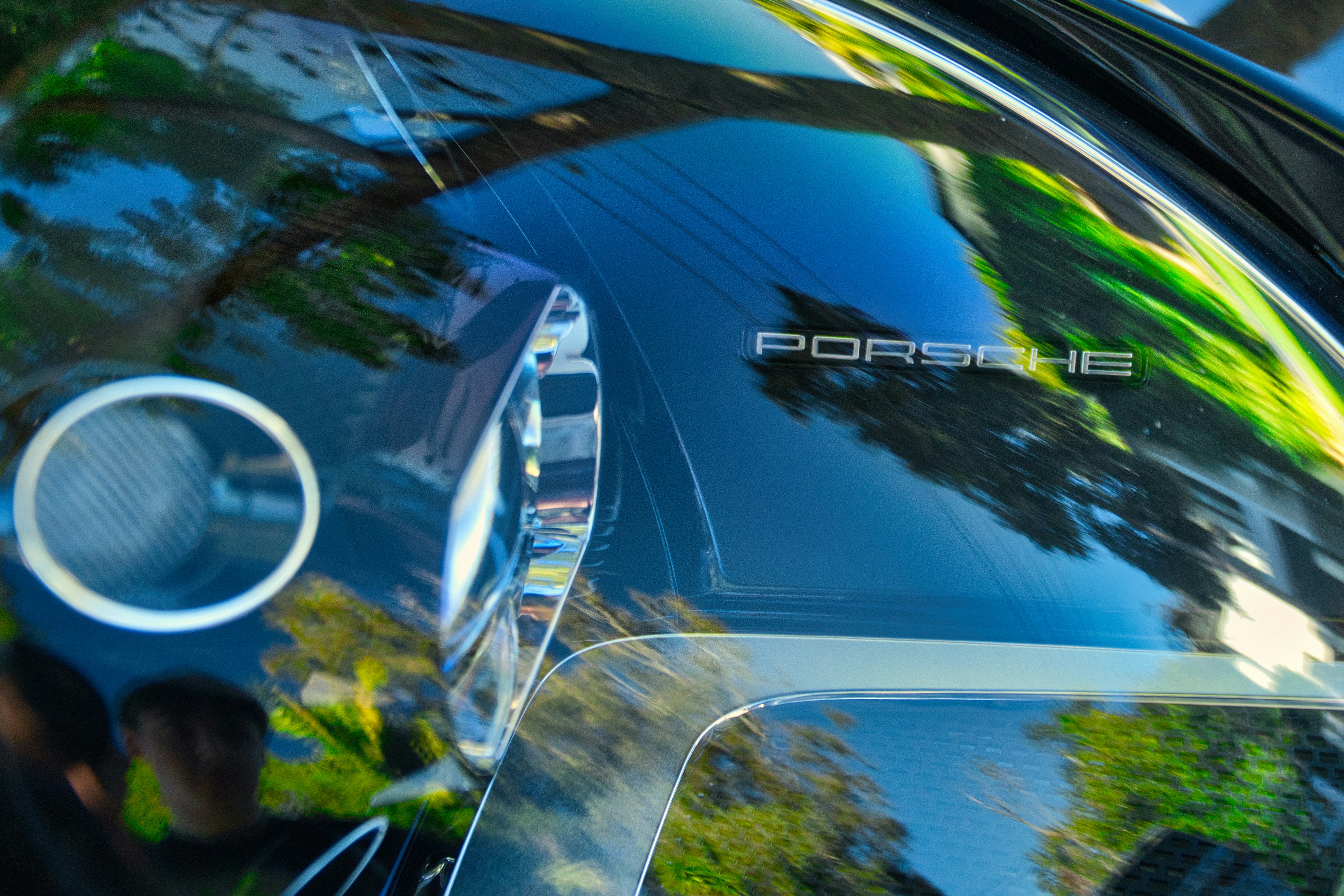 Porsche Badge in Motion: Glints of Color on a Curved Hood