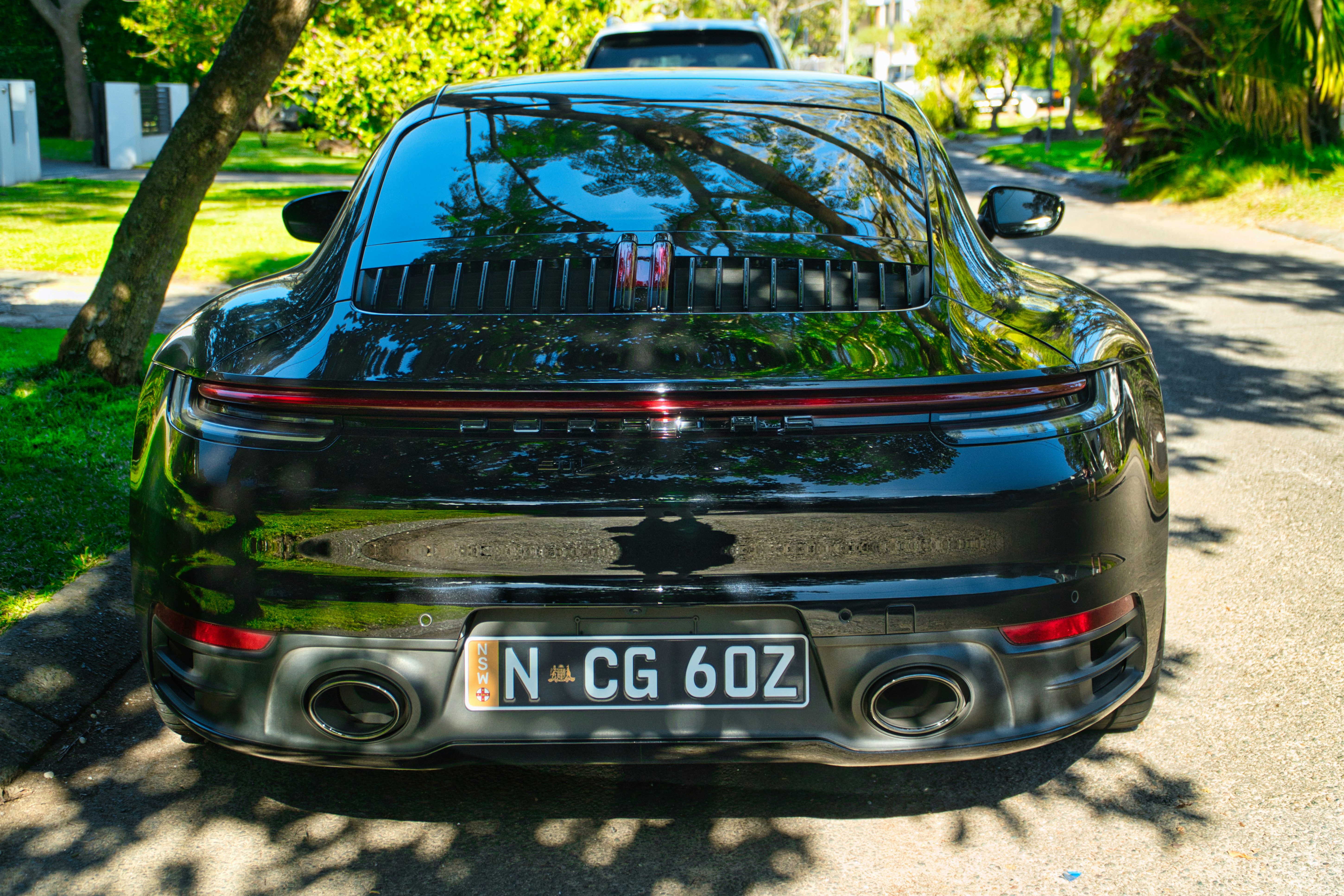 Rear View of a Sleek Black Porsche on a Sunlit Suburban Street