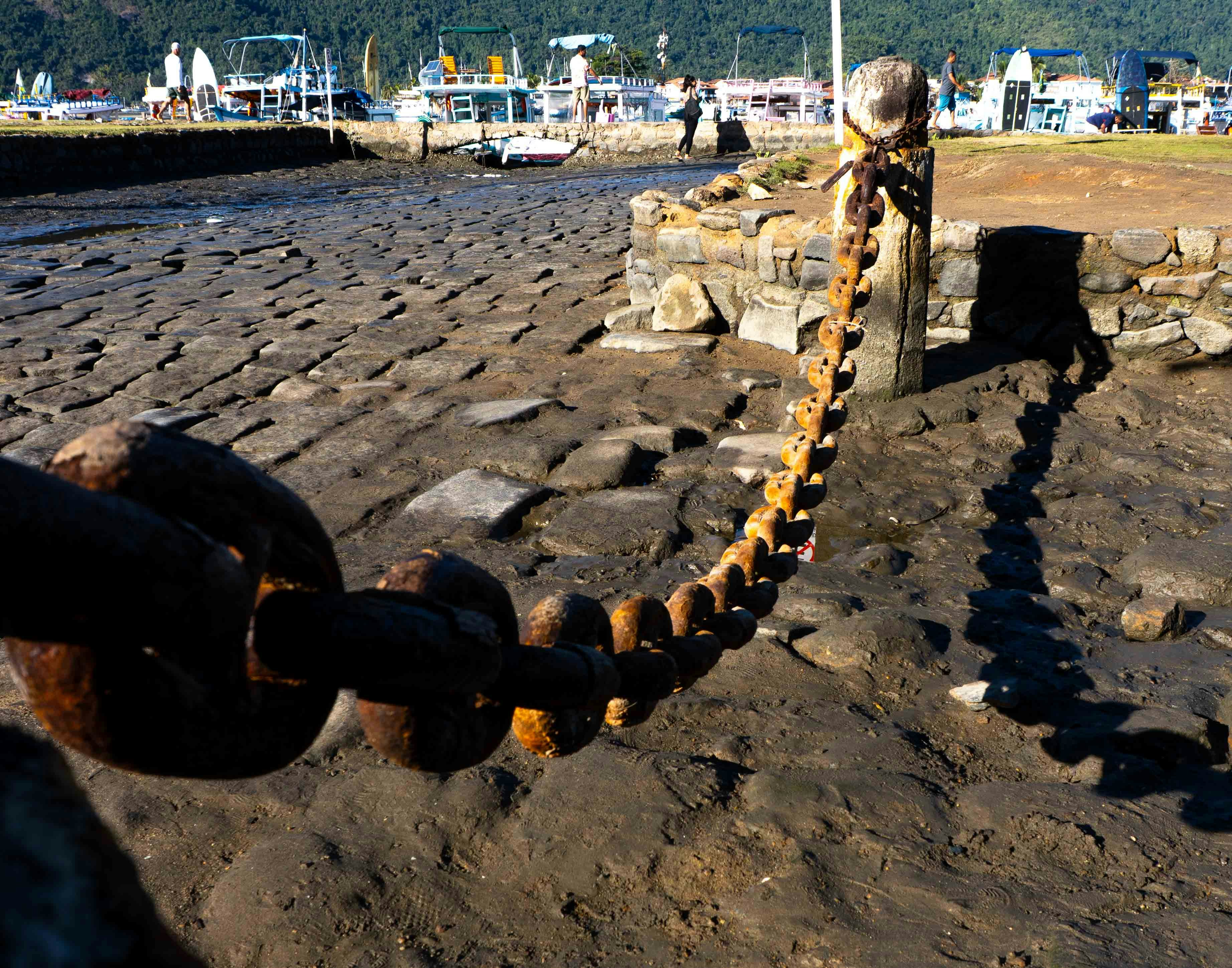 Rusty Chain Leading Toward a Rocky Quay